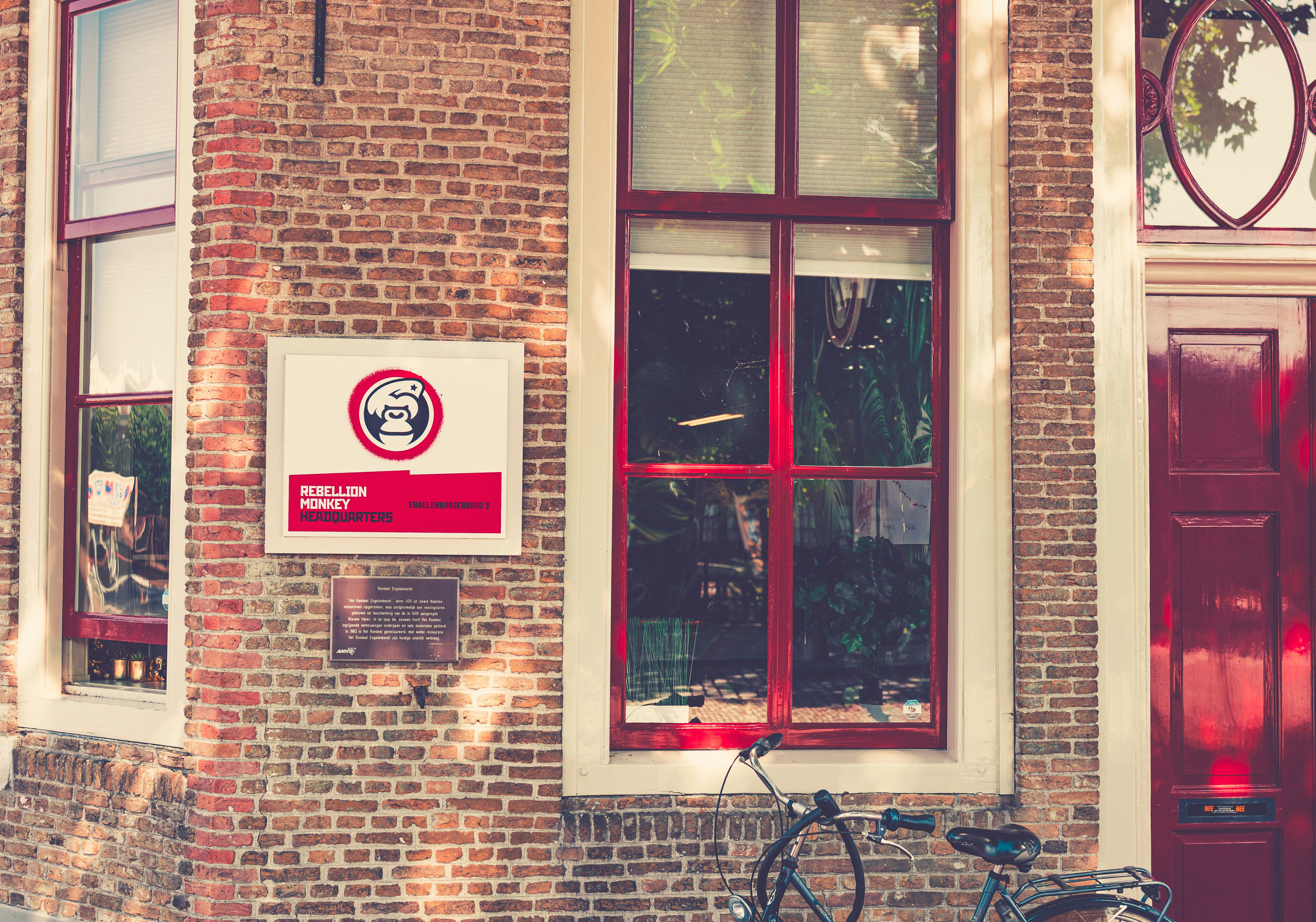 Brick building with red-framed windows and a bicycle.