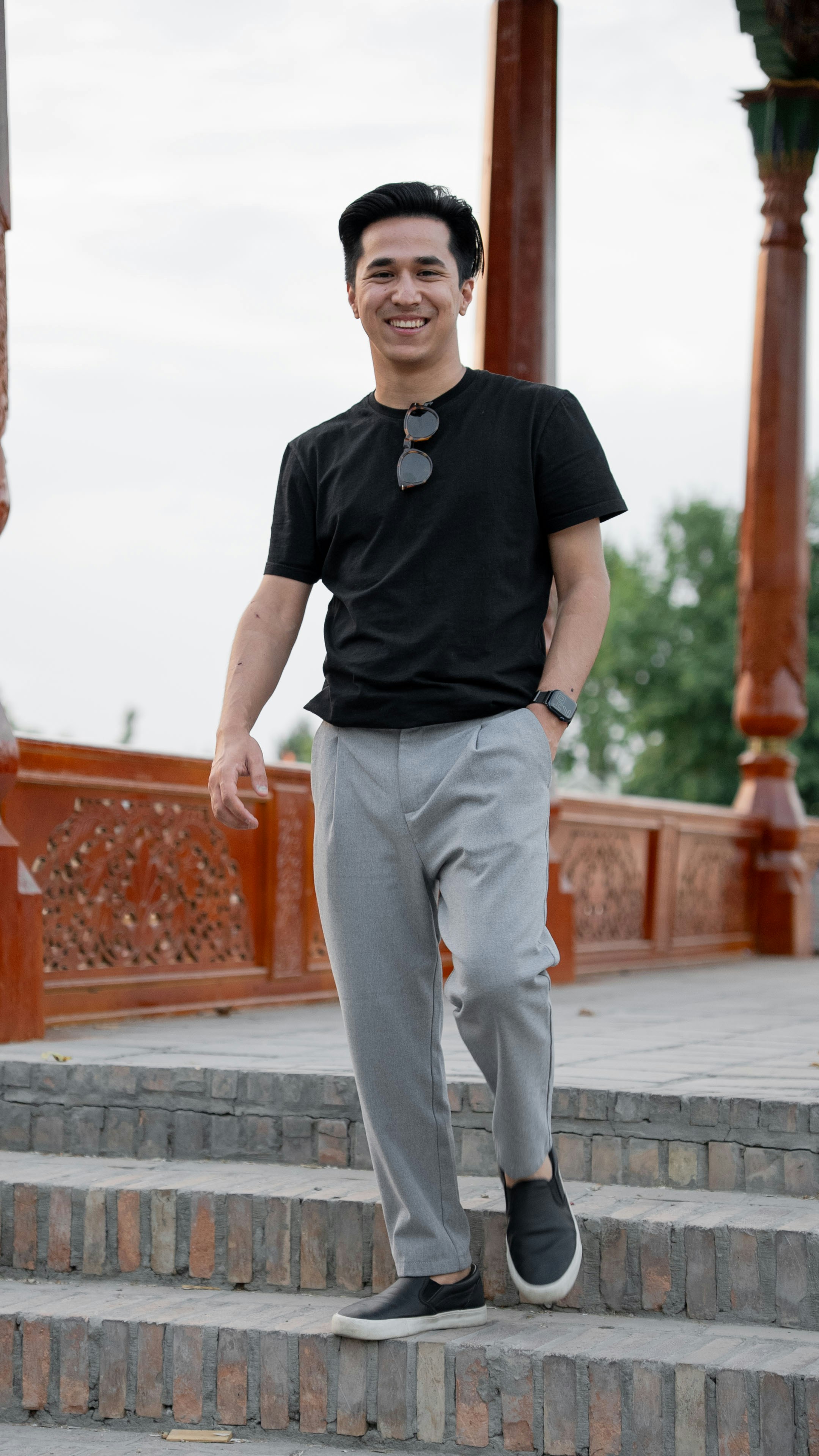 Sunlit stride: a confident smile on a man in black tee and gray joggers