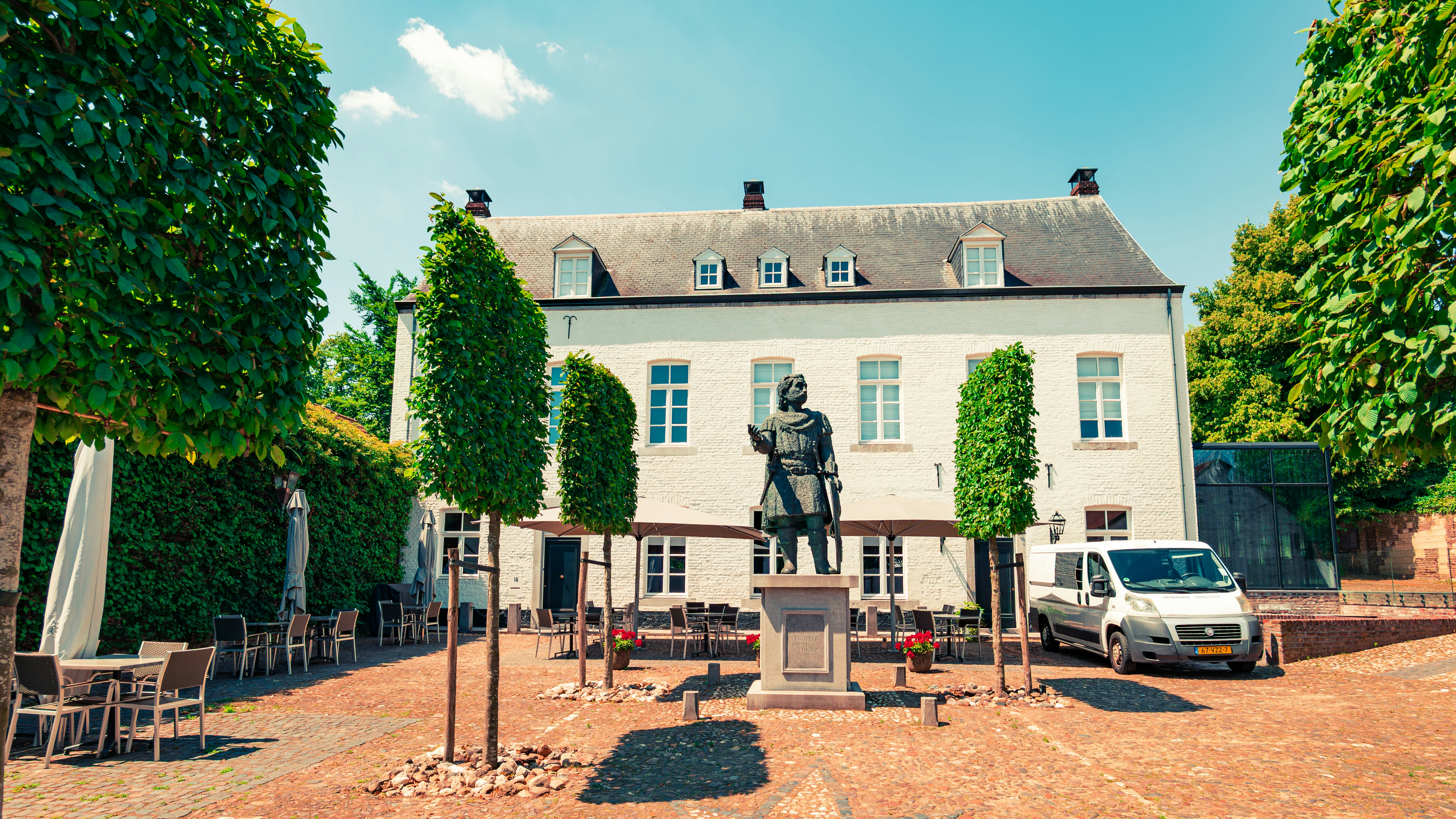 Statue in front of a white building with trees