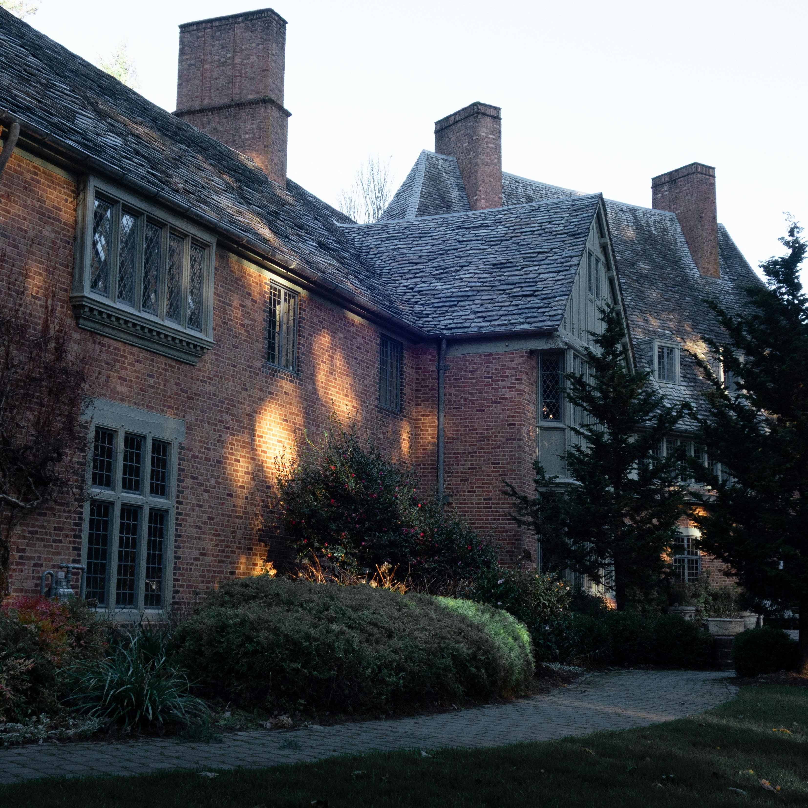 A large brick house with a gray roof and trees. photo – Free ...