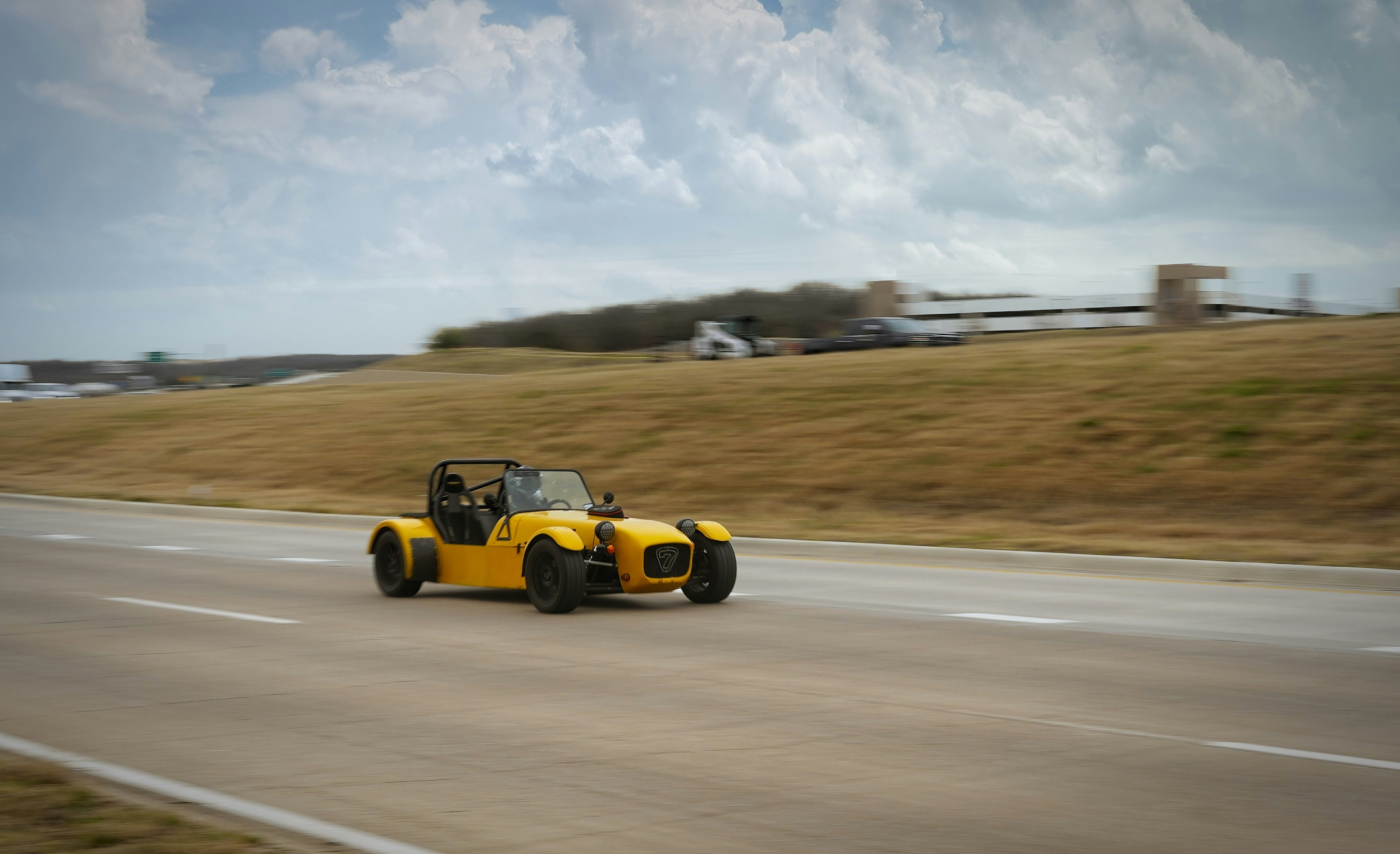 A yellow sports car driving on a highway. photo – Free Road Image on ...