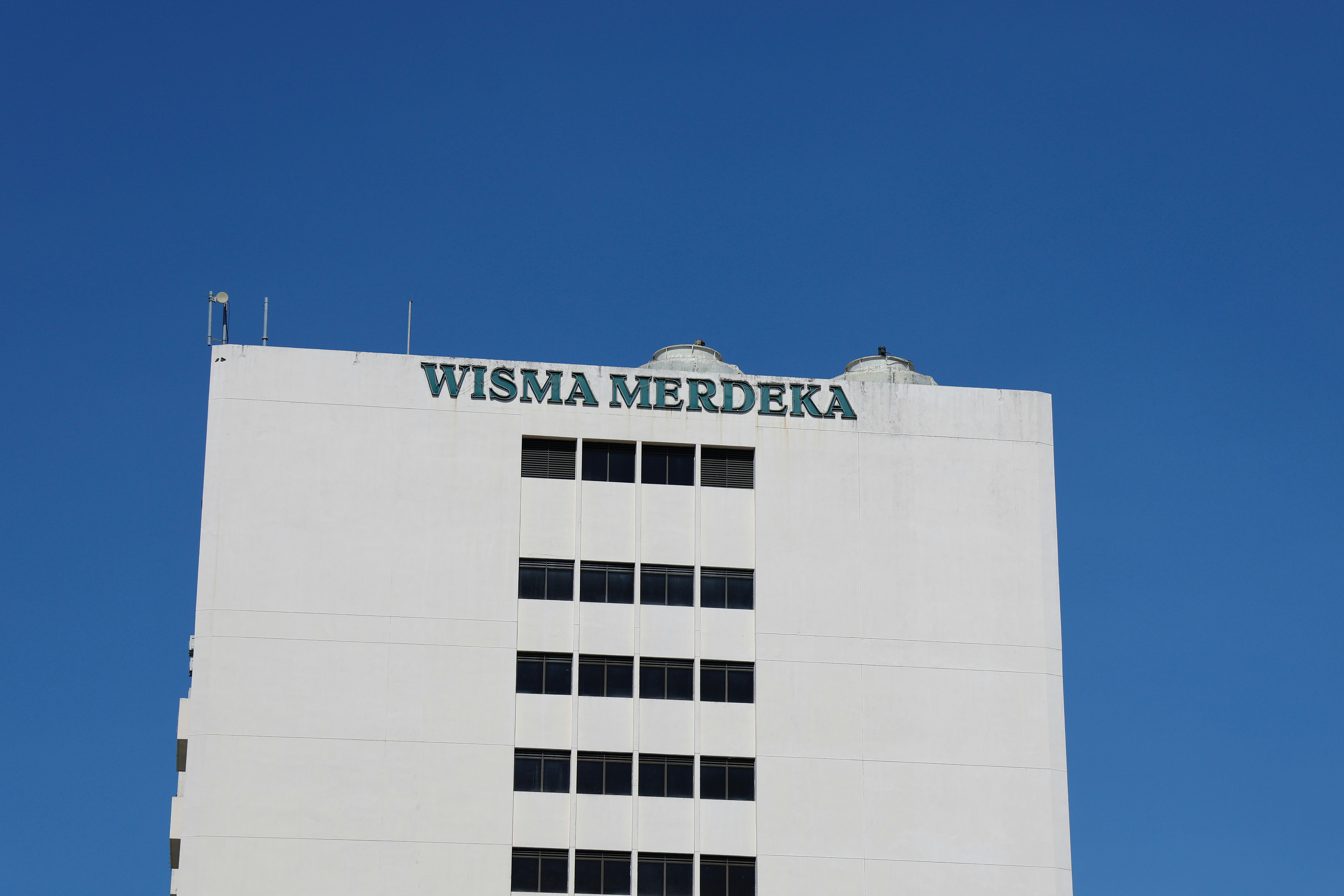White Facade Rising to a Clear Sky with Wisma Merdeka Sign