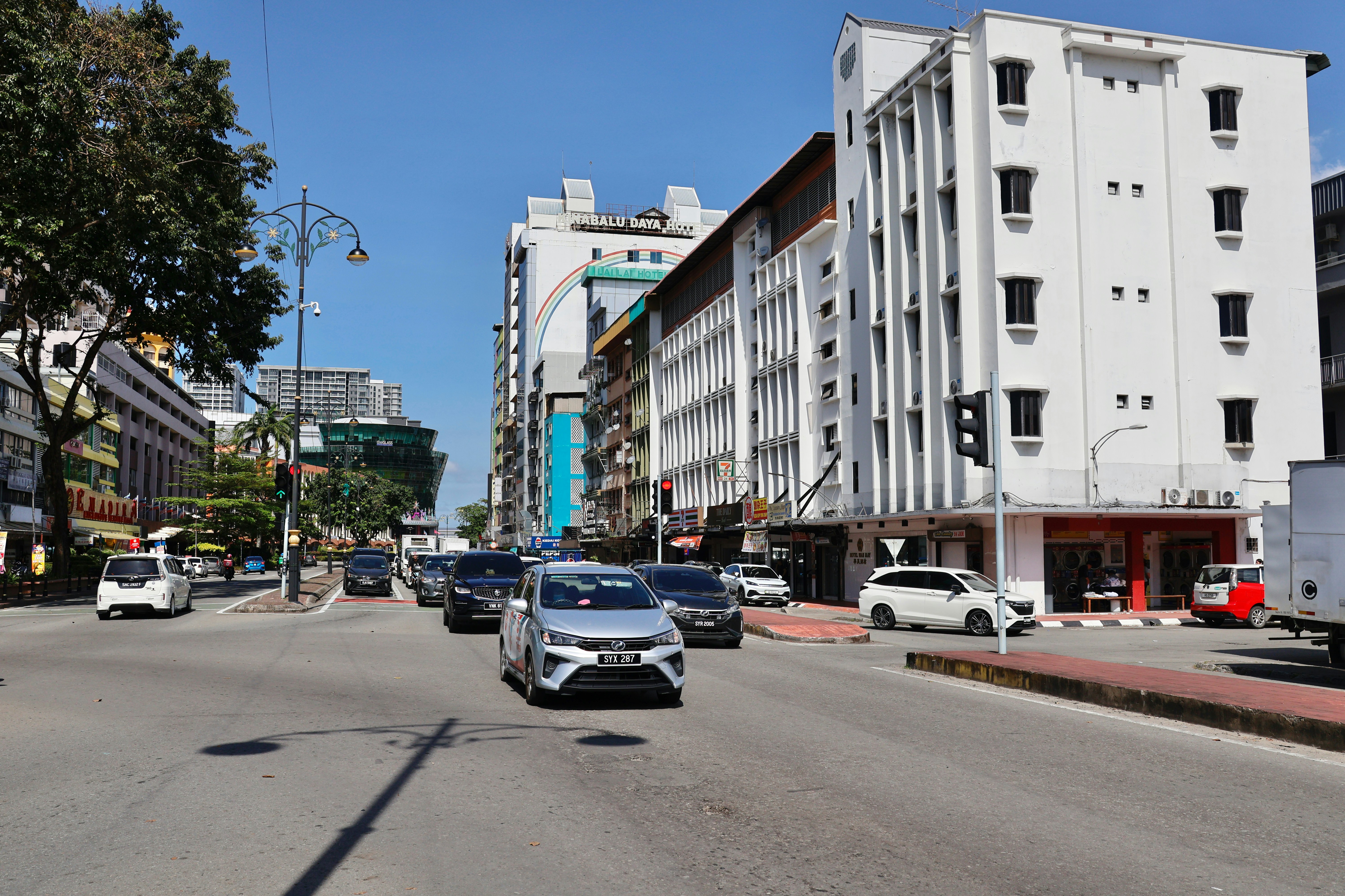 Cars driving on a city street with buildings. photo – Free Car Image on ...