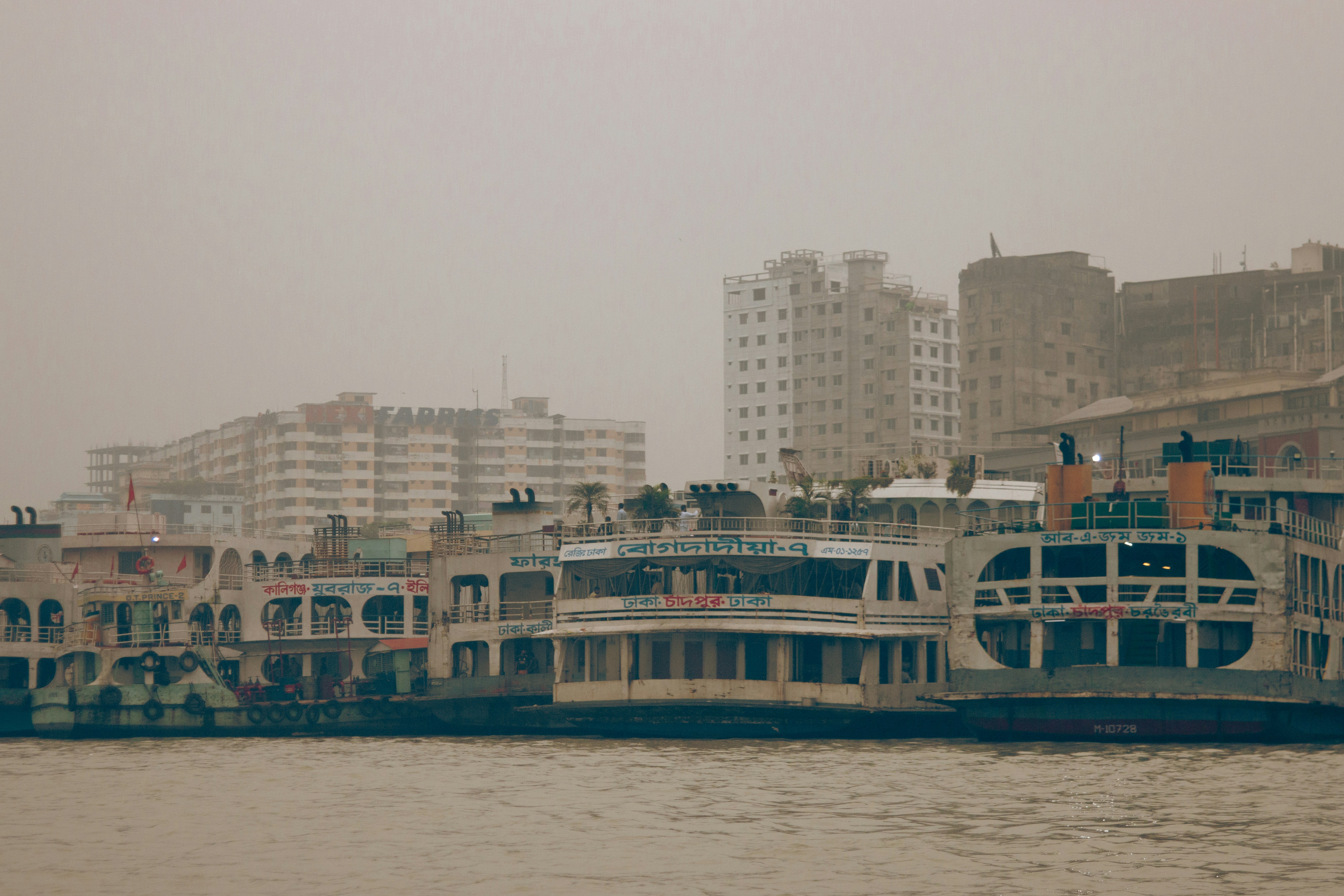 Riverfront Ferries at Dusk: A Row of Floating Lounges Against a Riverside Skyline