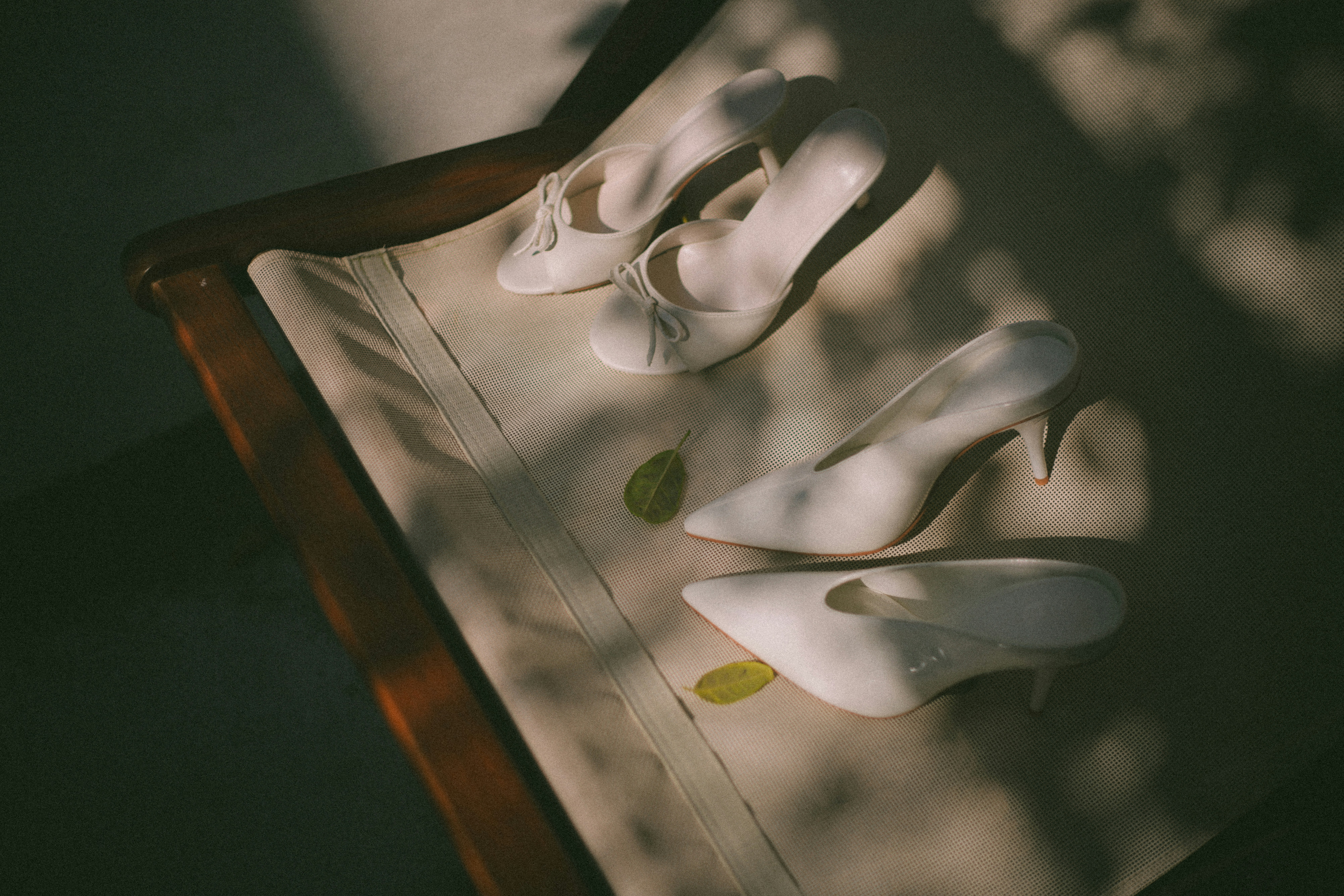 Shadowed Elegance: White Heels Resting on a Wooden Rail