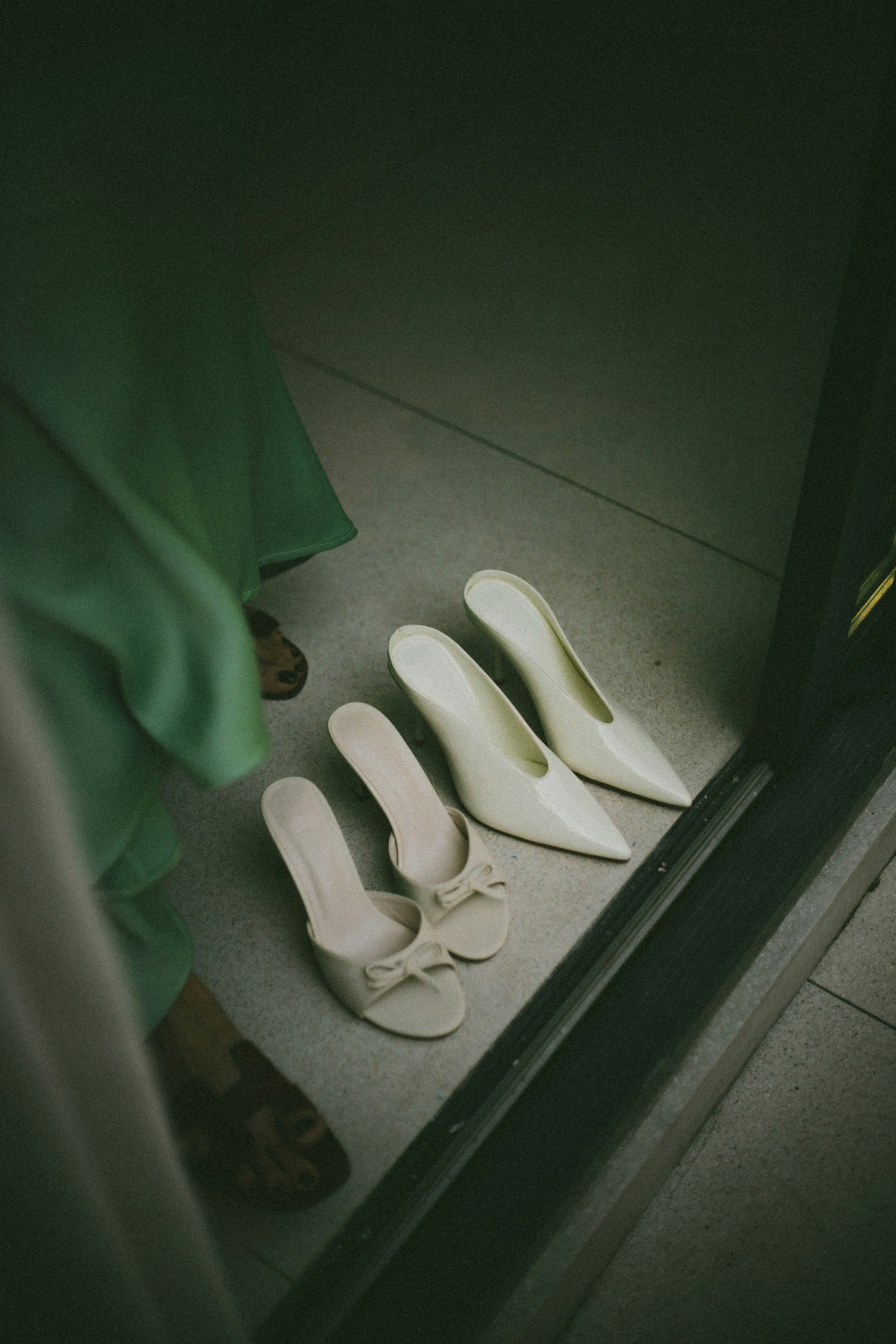 Hidden Steps: White Heels Await Outside a Quiet Boutique