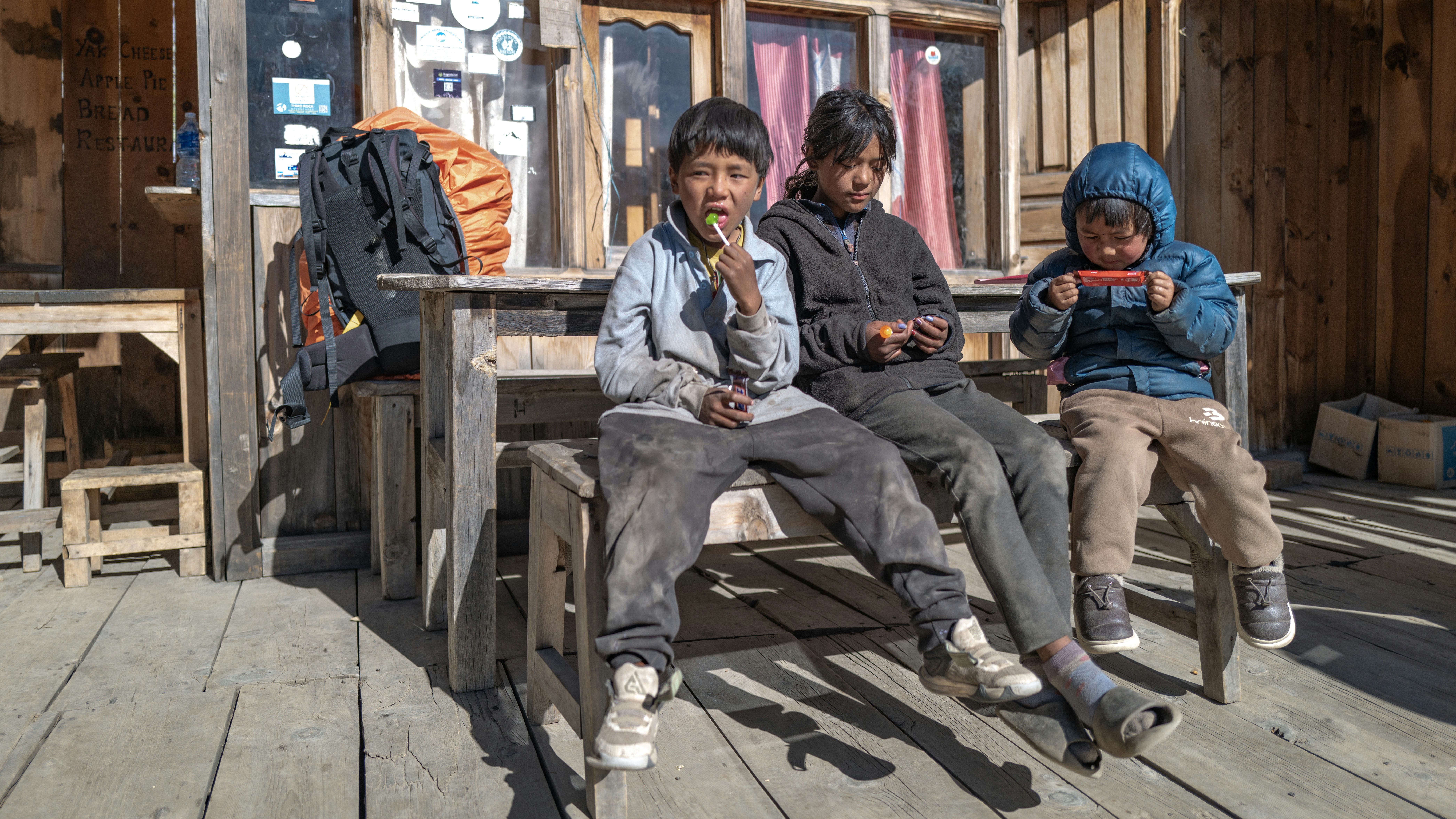 Three Sitters on a Wooden Porch in a Mountain Village