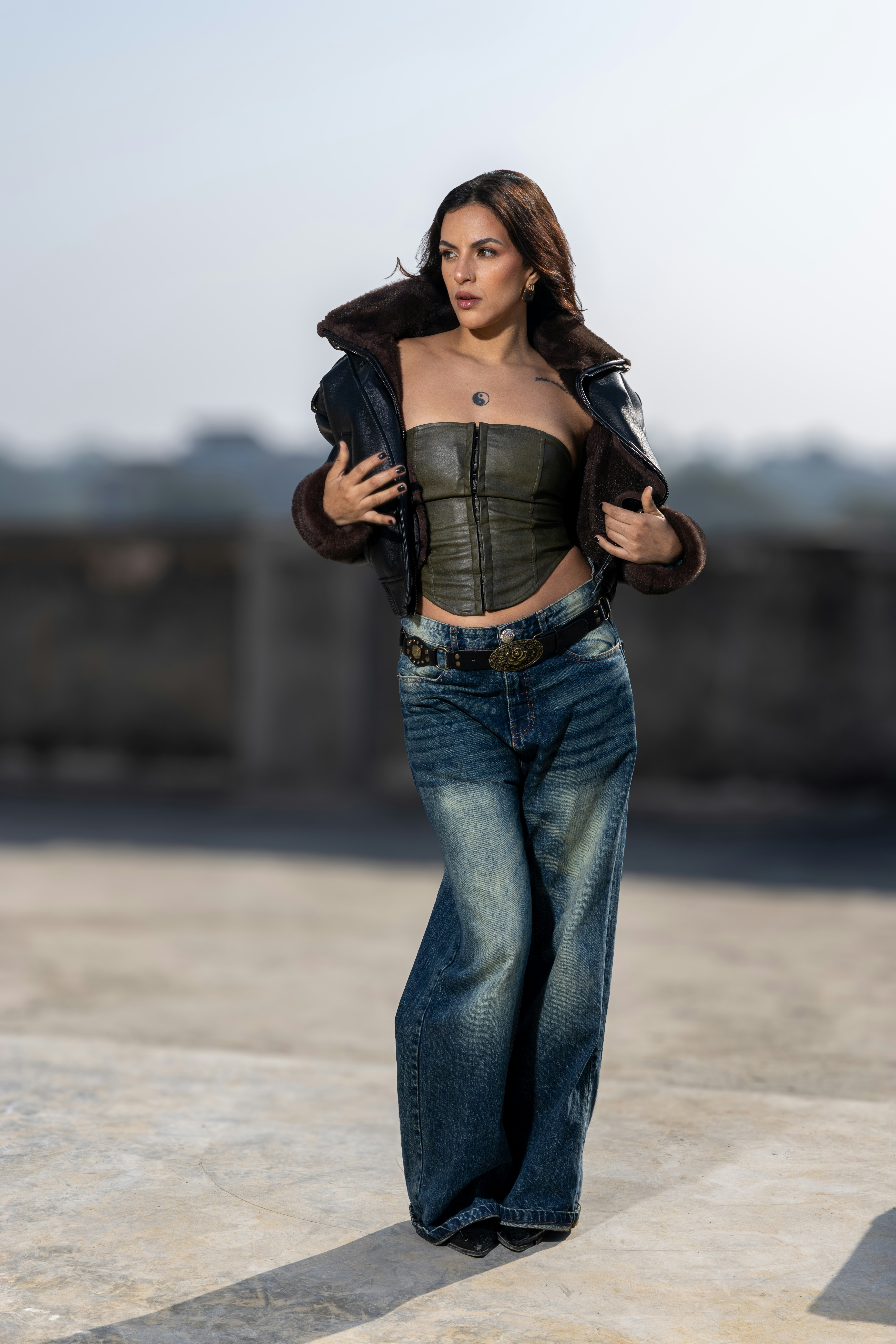 Woman in leather corset, bomber jacket, and jeans