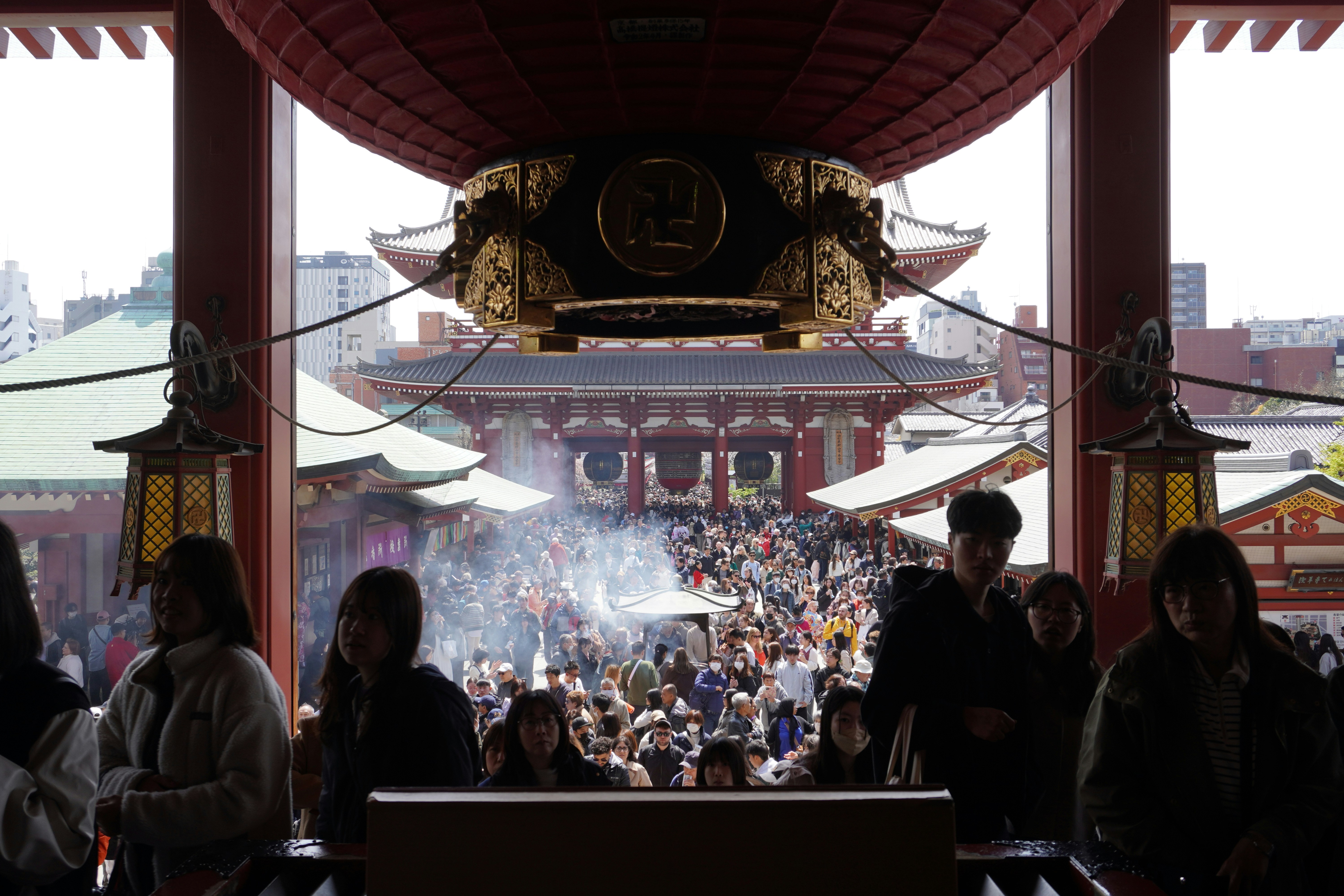 Crowded Temple Courtyard Framed by Ornate Roof—A Street-Level View into Tradition