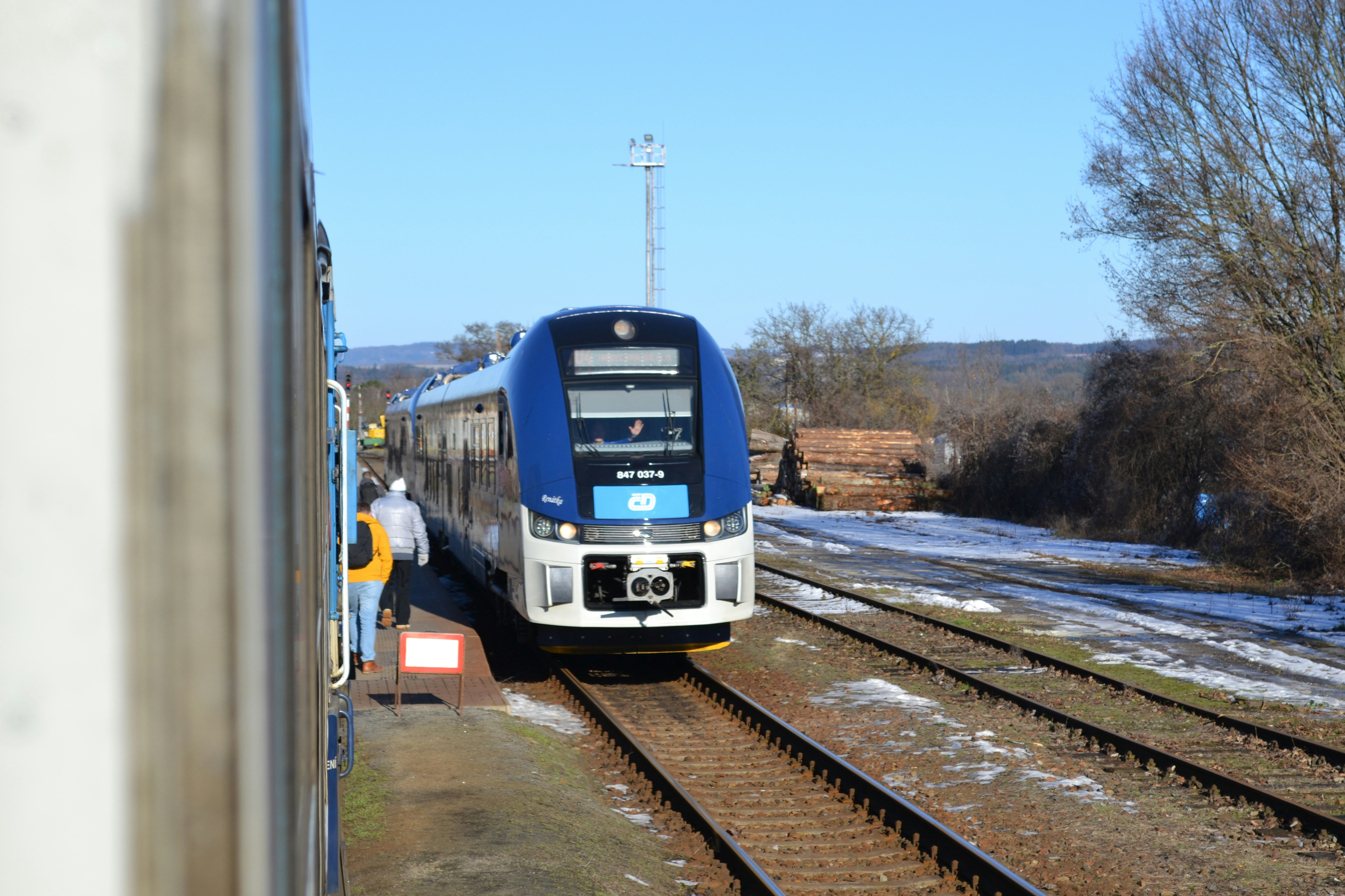 Blue locomotive approaching from the right on a snow-dusted track
