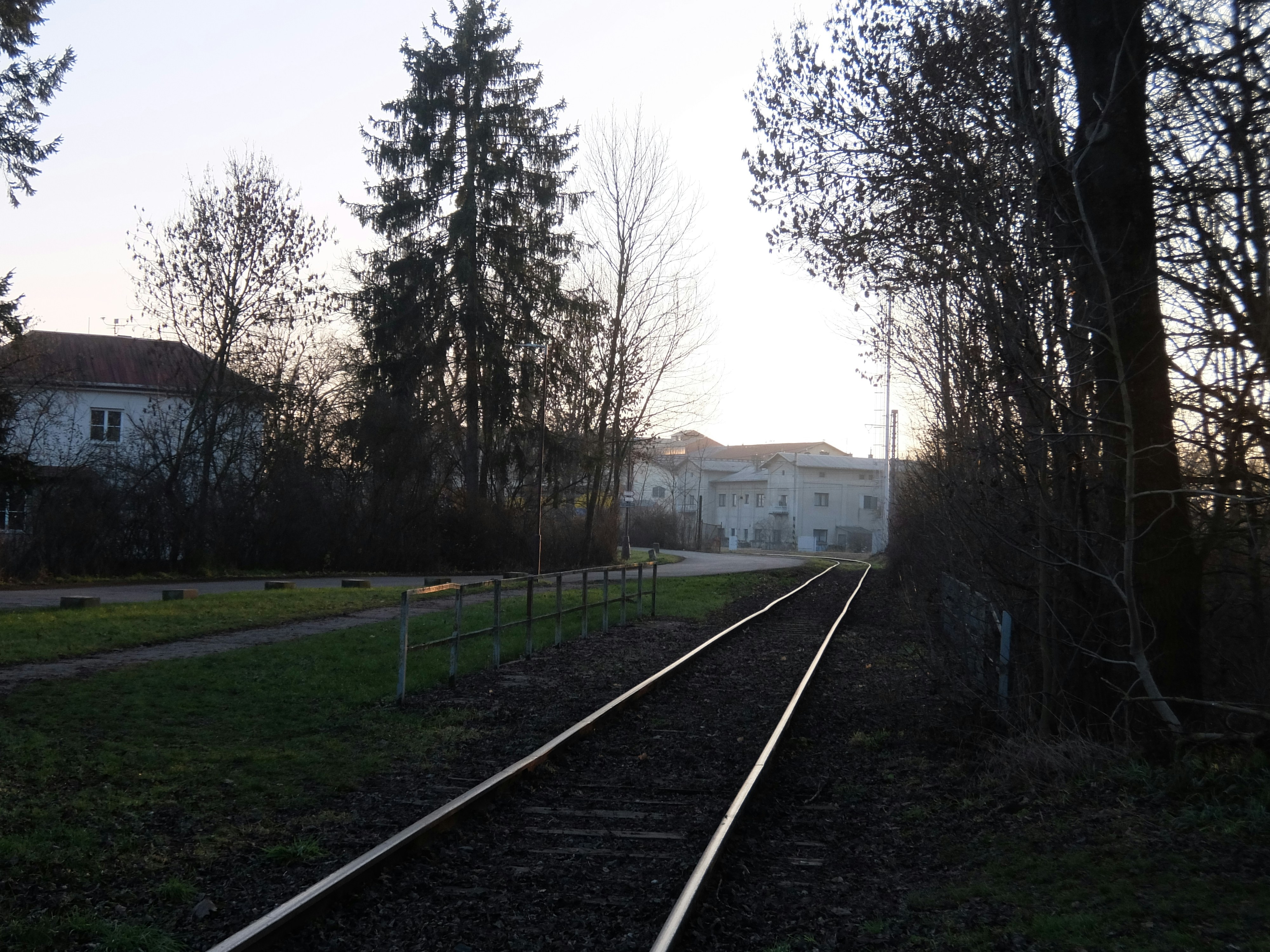 Railroad tracks leading towards buildings at dusk.