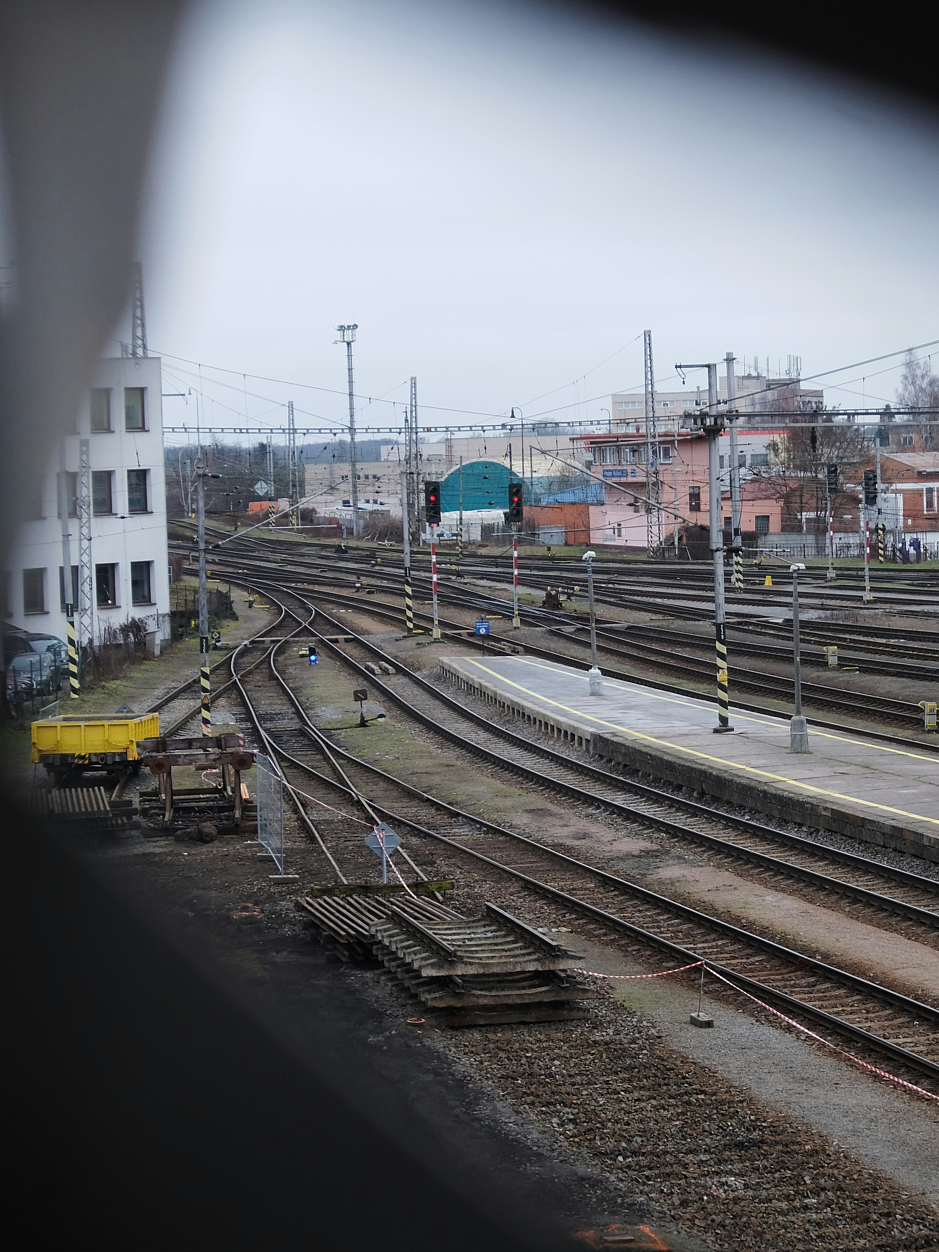 Train tracks converge at a busy station with buildings.