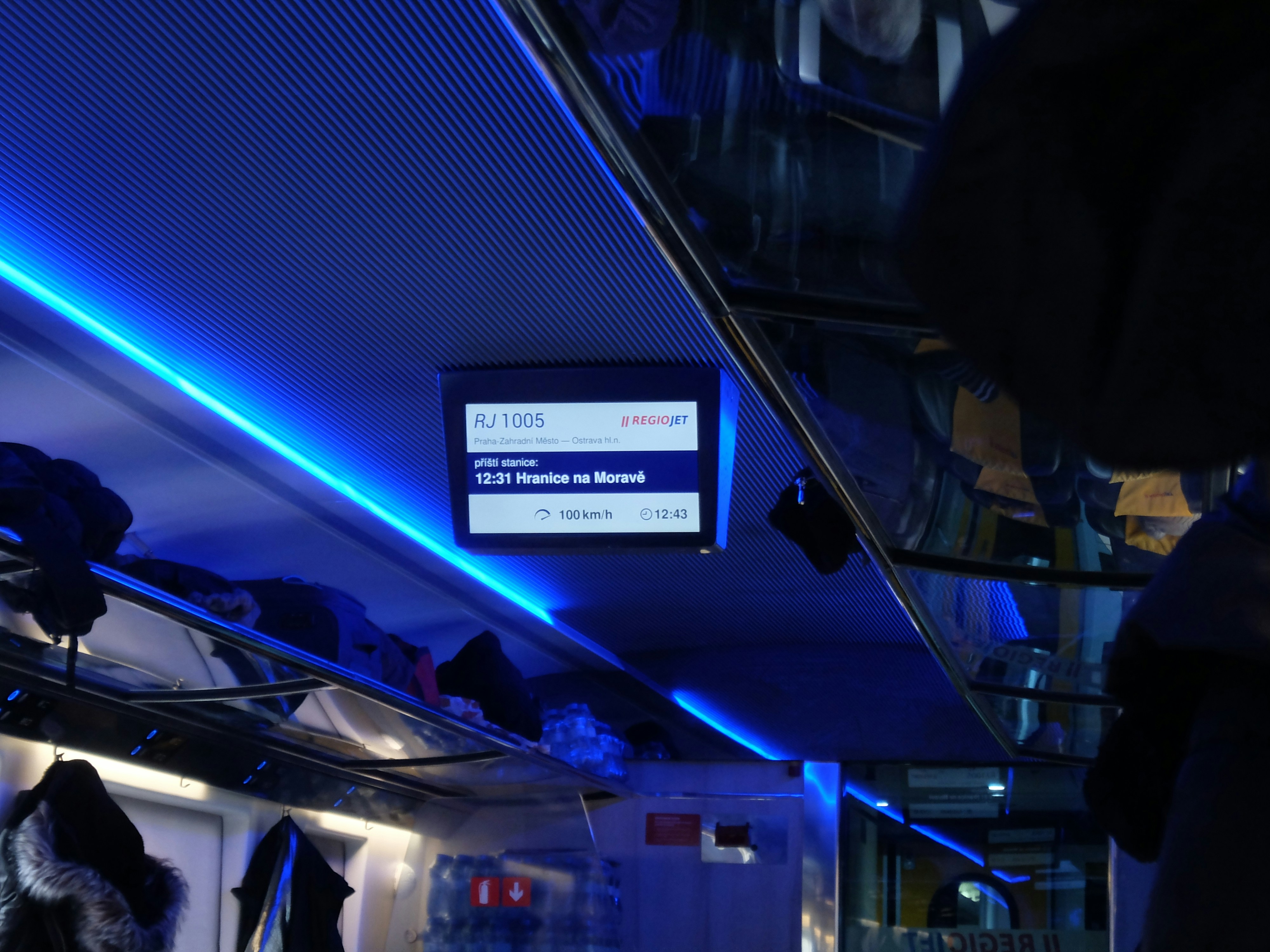 Neon Corridor Aboard: Blue Lights, Screen Sign, and Reflections