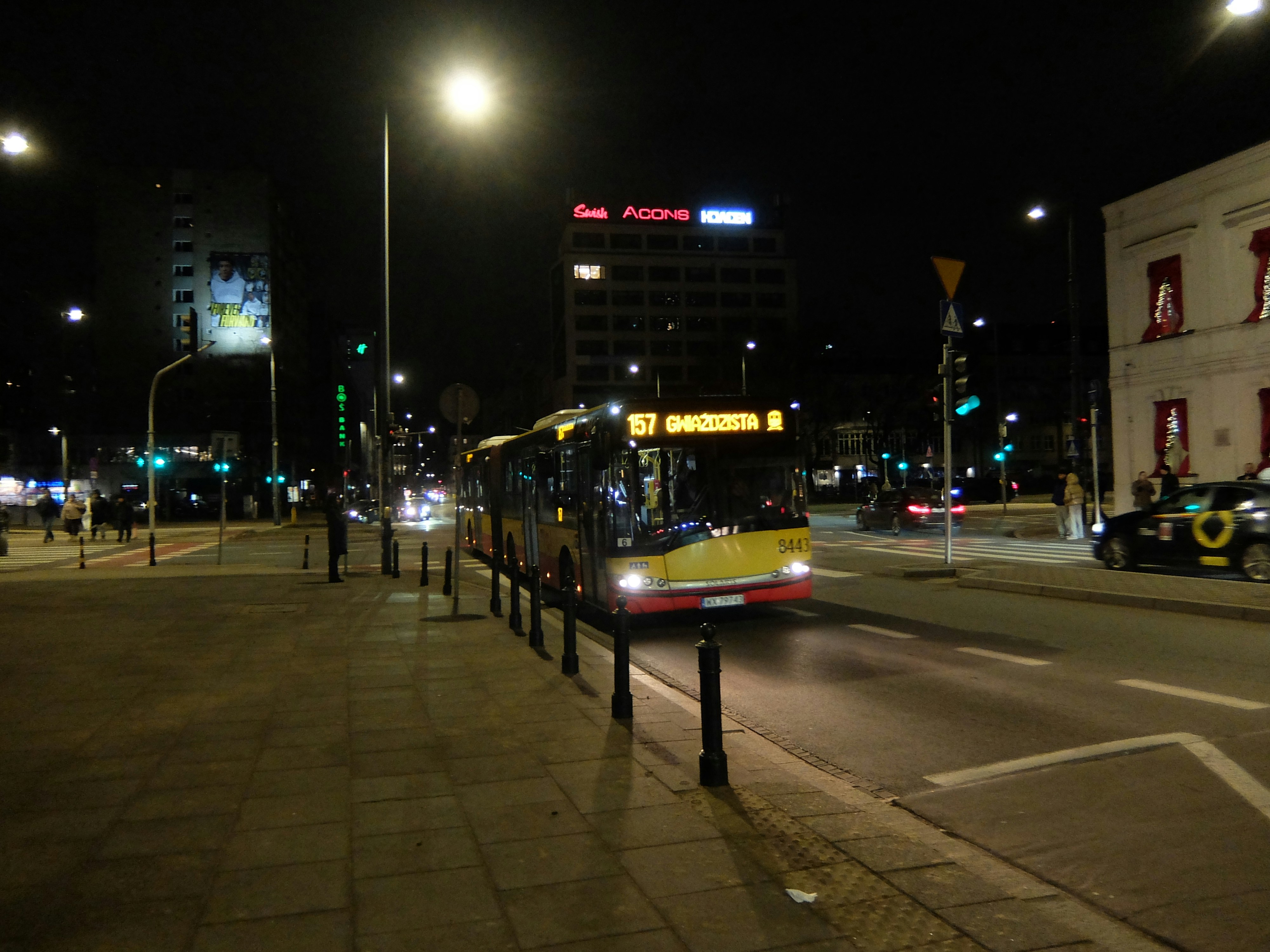 A bus drives down a city street at night.