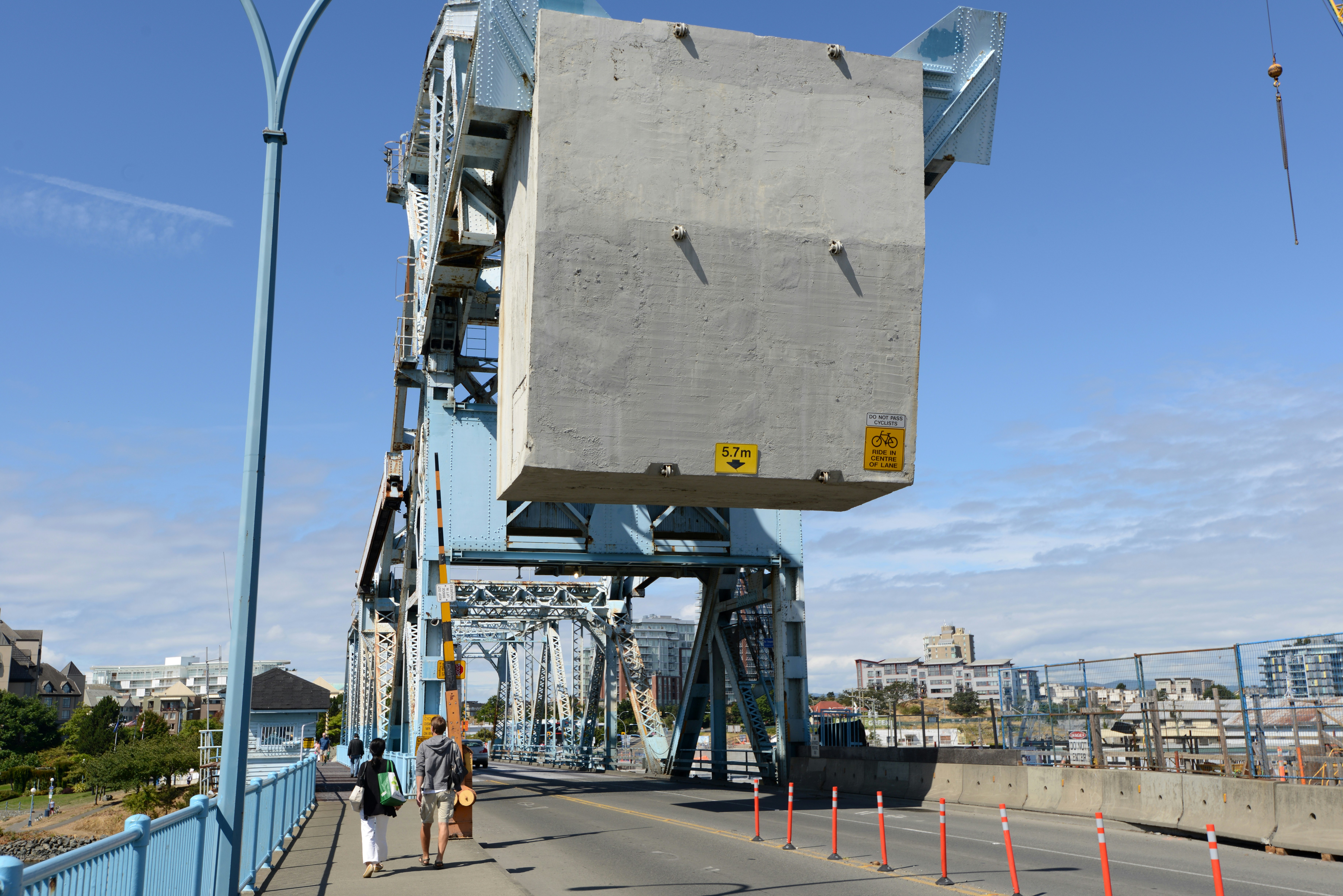 Blue Suspension Gate: Humans and Crane in the Midday Span