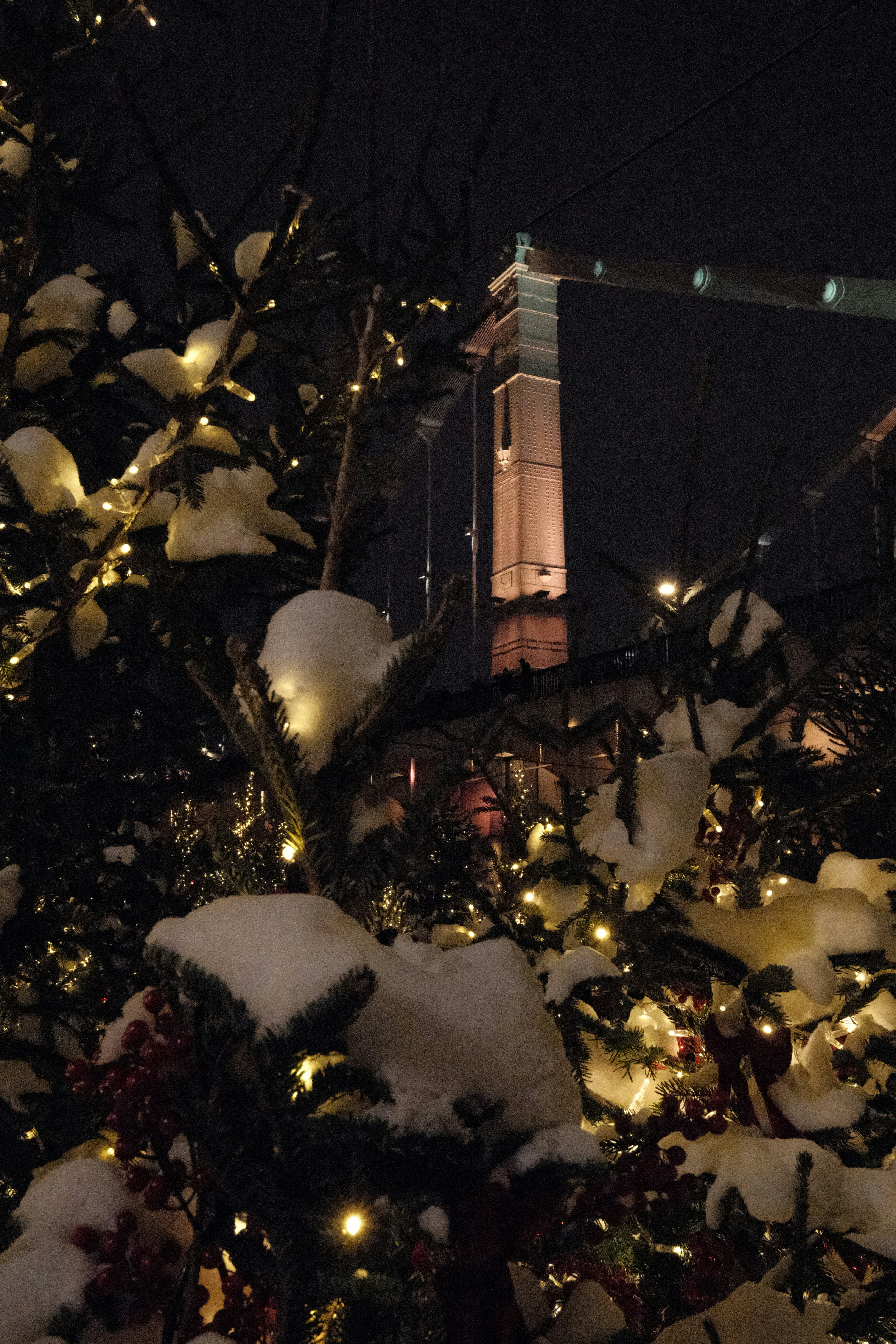 Illuminated tower among snowy garden lights