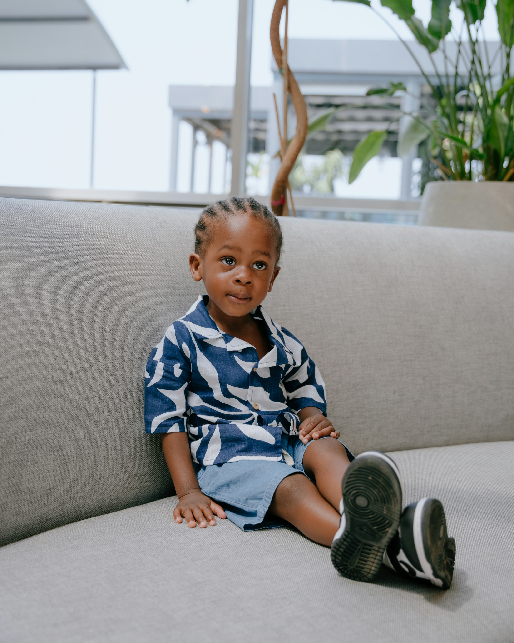 Portrait on a Quiet Lounge: A toddler in patterned shirt relaxes on a modern sofa