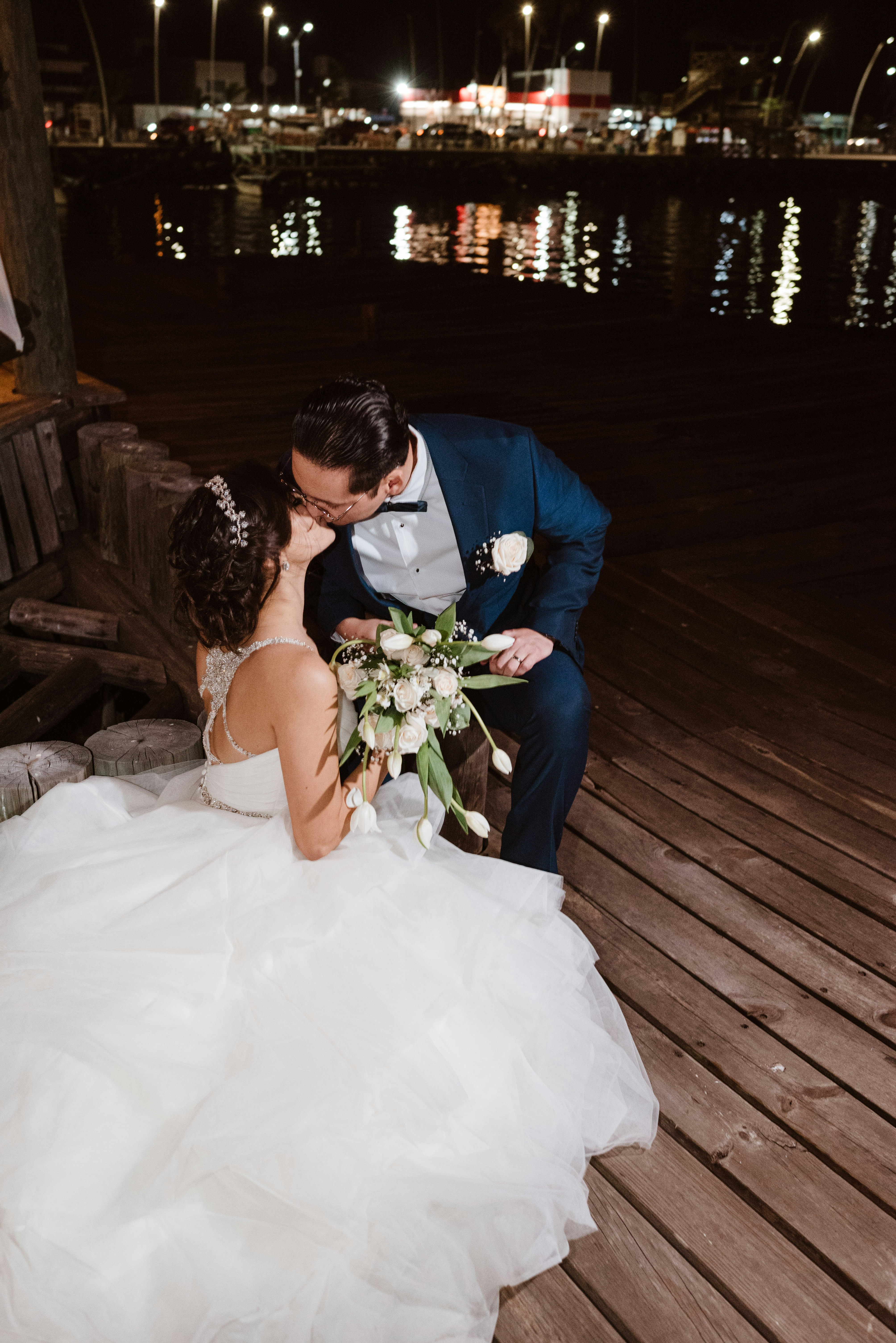 Kiss at the Waterfront: A Bride and Groom Share a Quiet Moment on the Dock