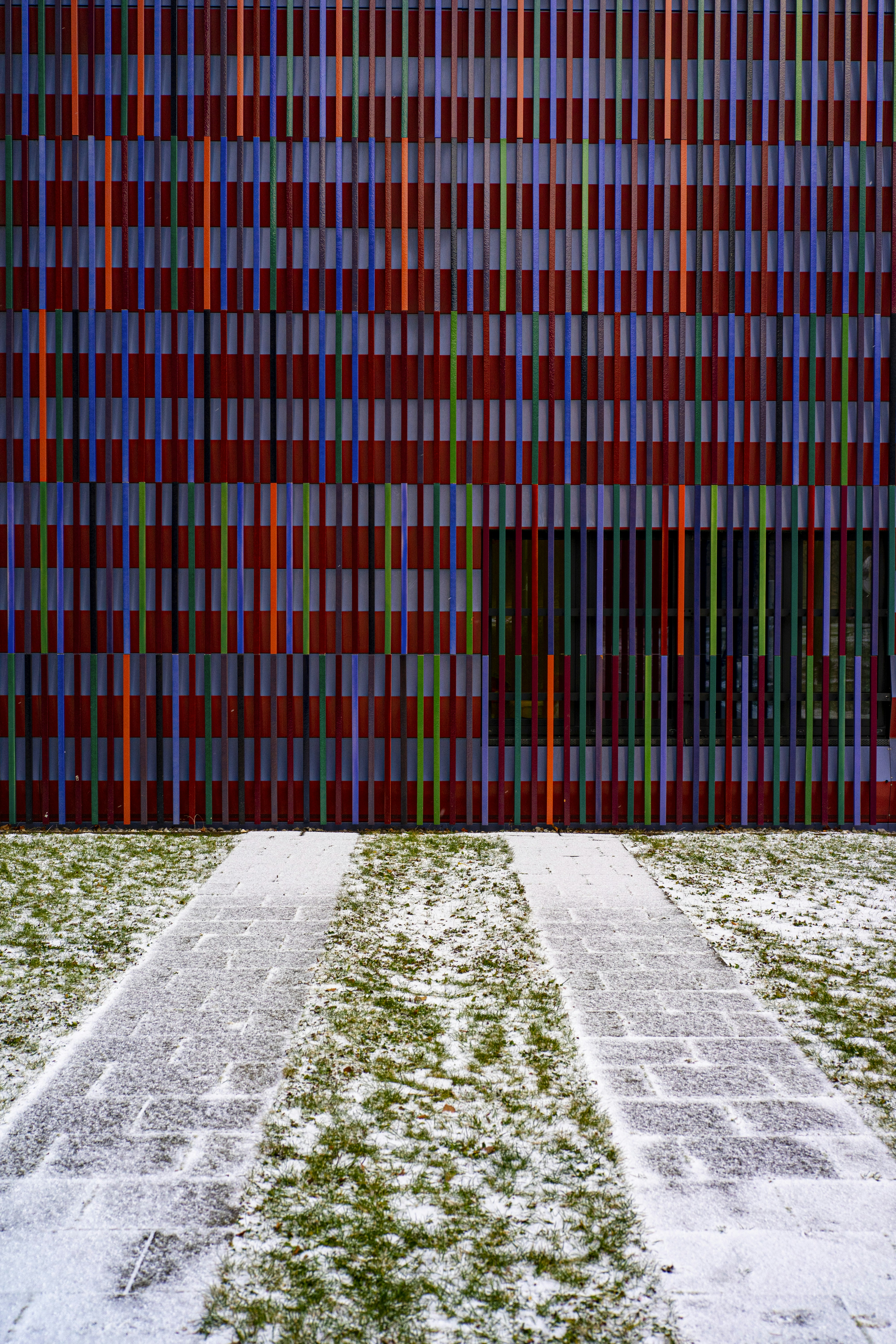 Colorful woven facade meeting a frost-kissed path