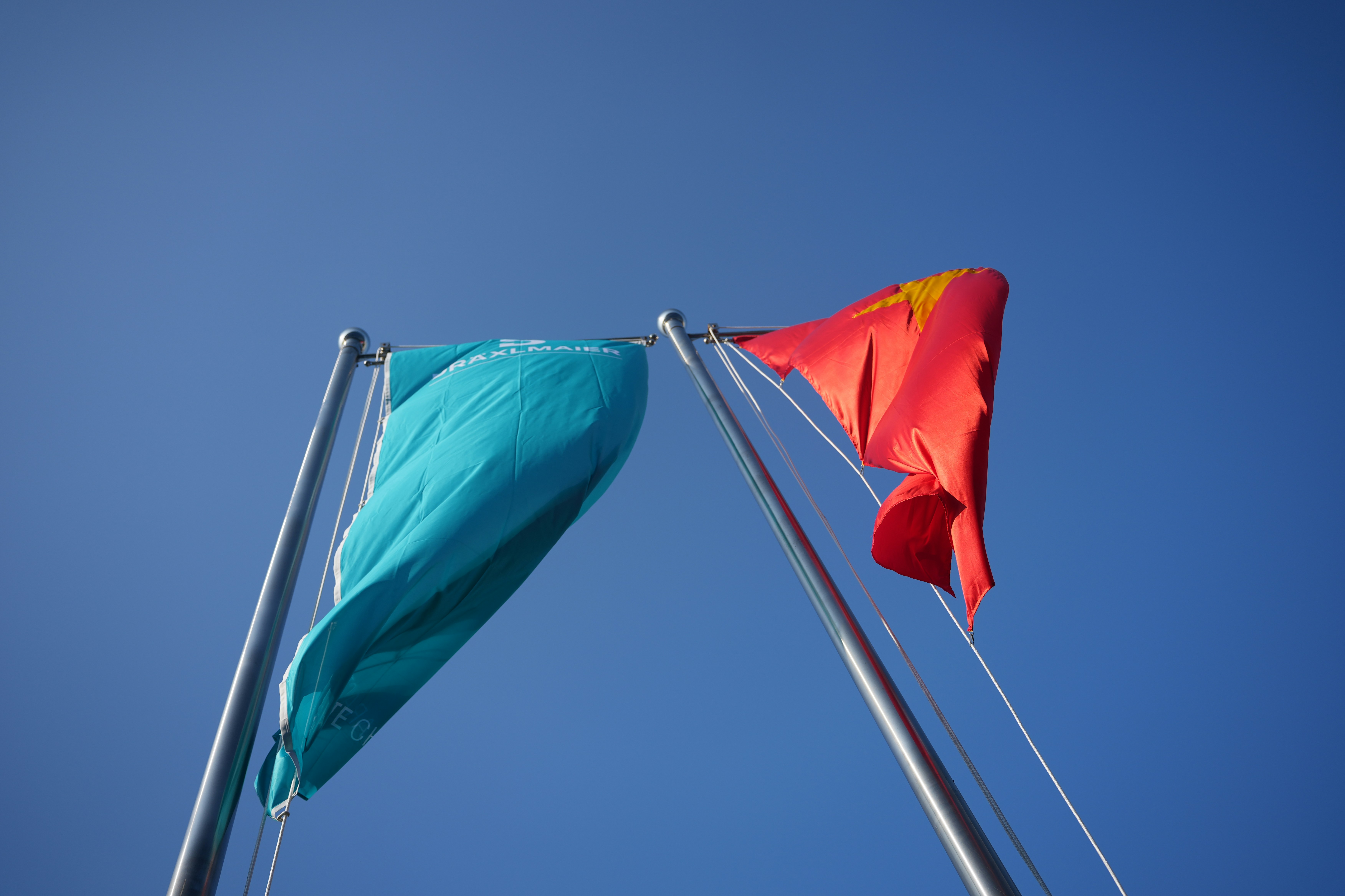 Azure and Ember: Flags Catch the Stray Breeze Against a Clear Sky