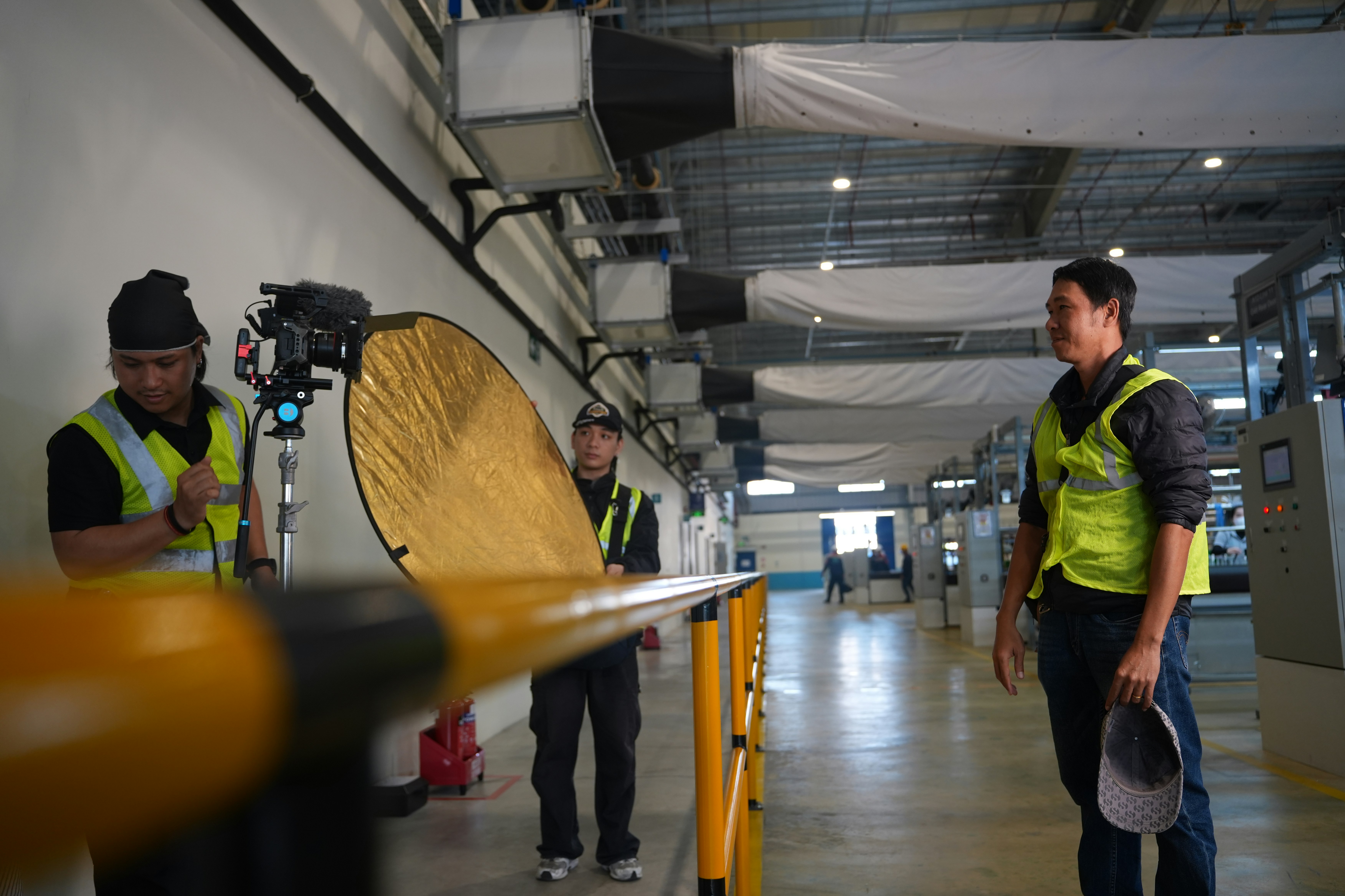 Crew in Neon Vests Navigates an Industrial Shoot in a Bright Factory Hall