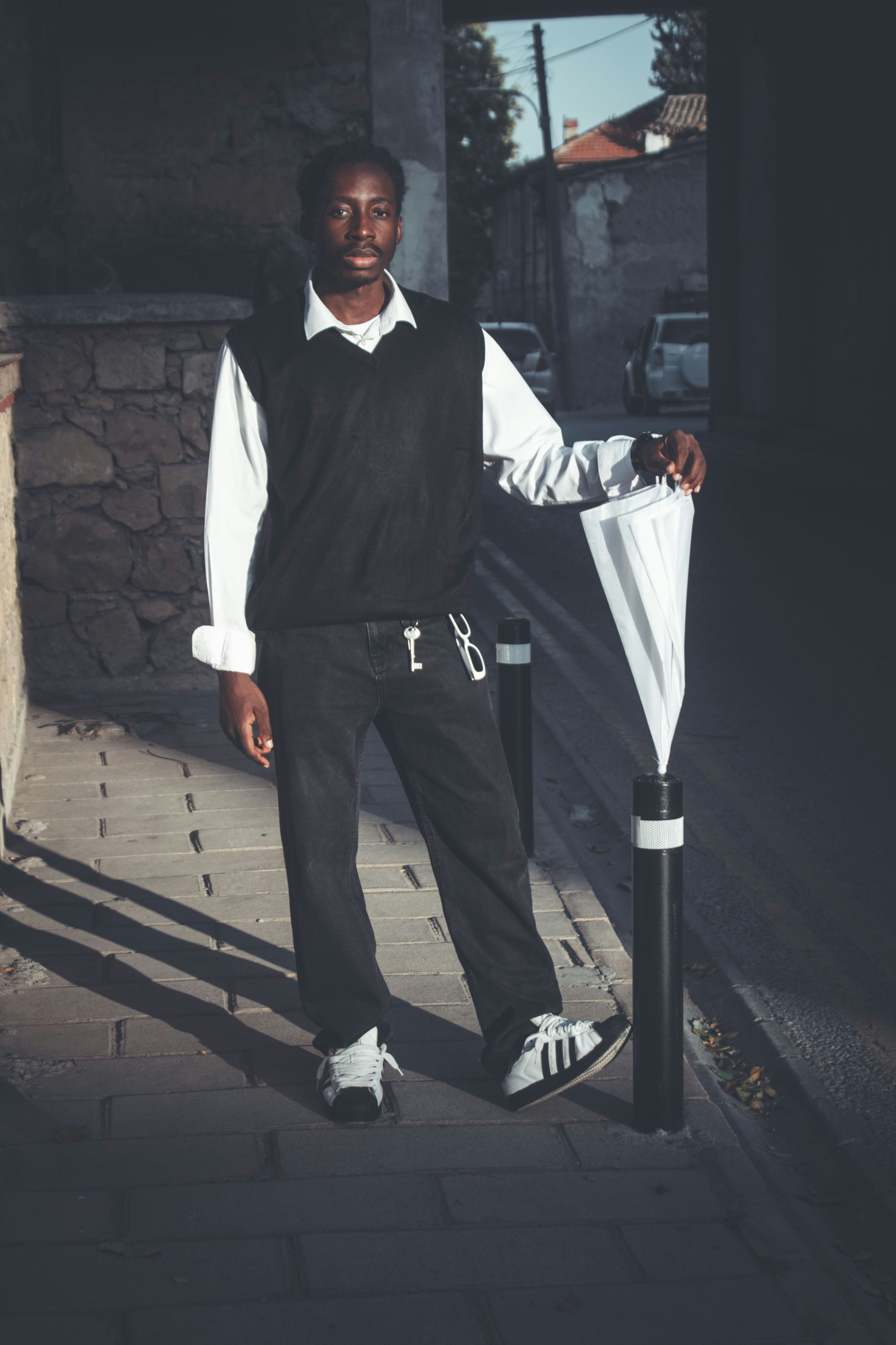 Streetwise in the Noon Light: A Casual Portrait by the Umbrella Post