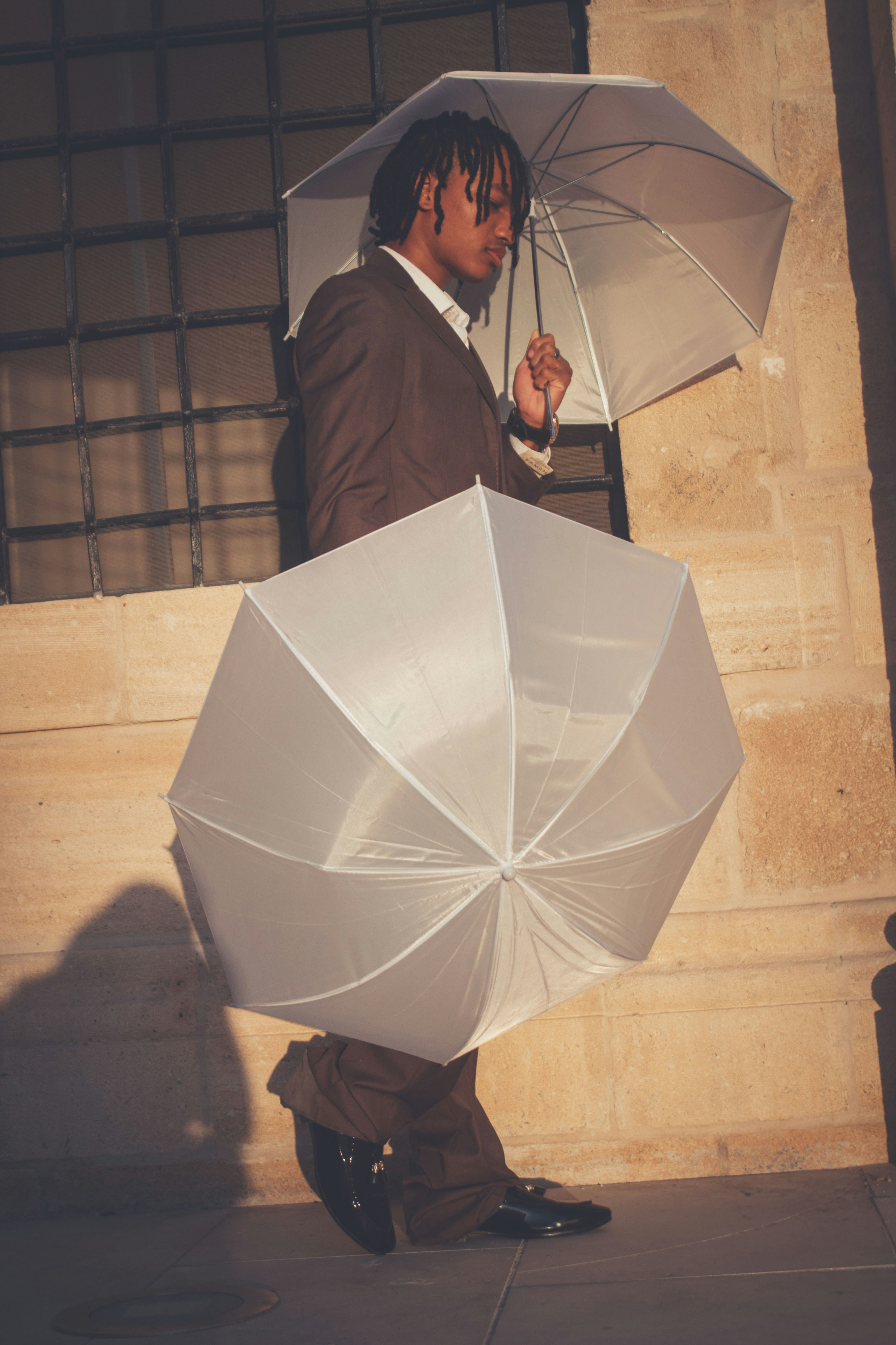 Silk Shadows: A Gentleman with White Umbrellas Beneath Evening Stone
