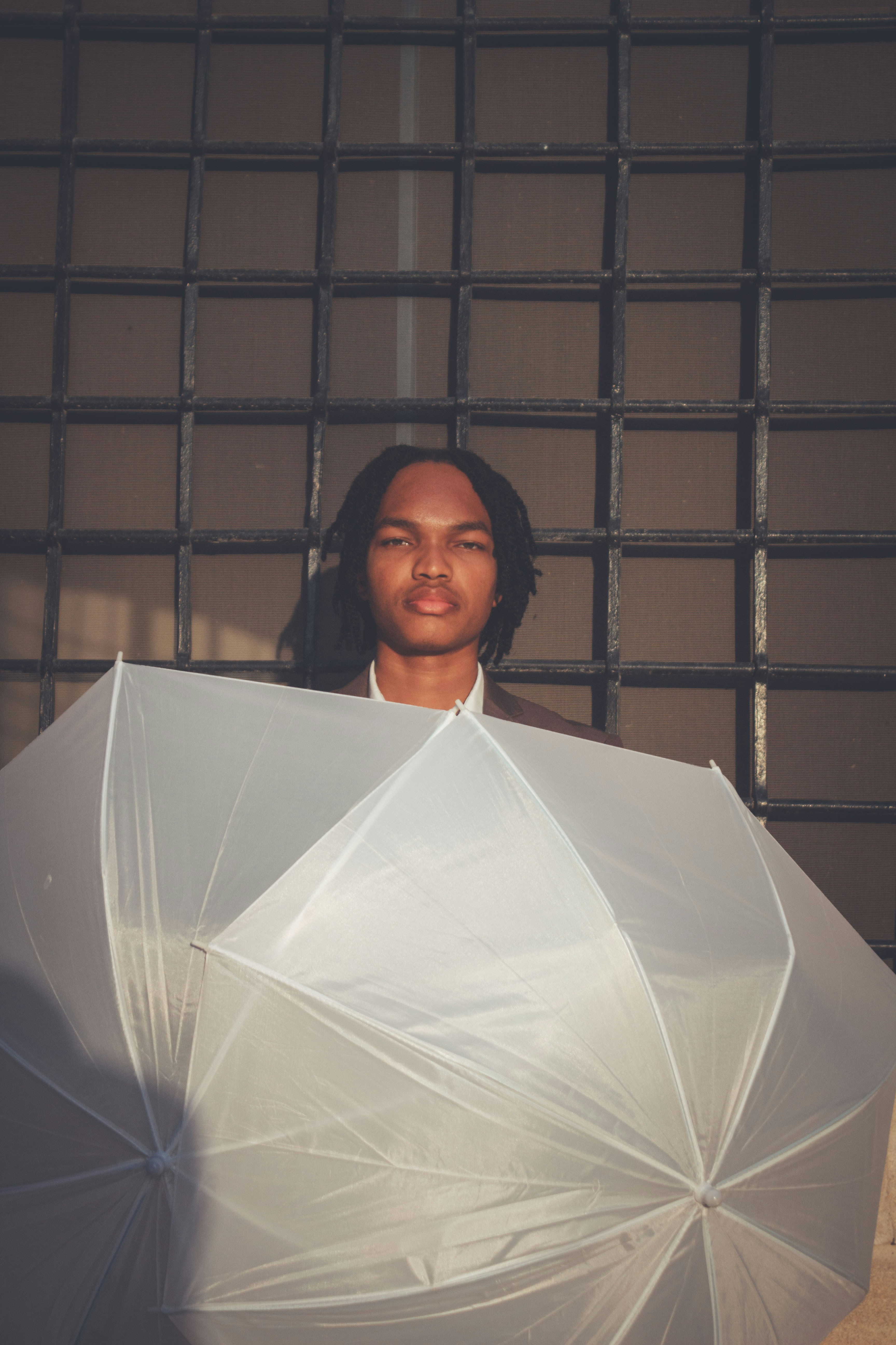 Portrait under a translucent umbrella: quiet confidence amid geometric backdrop