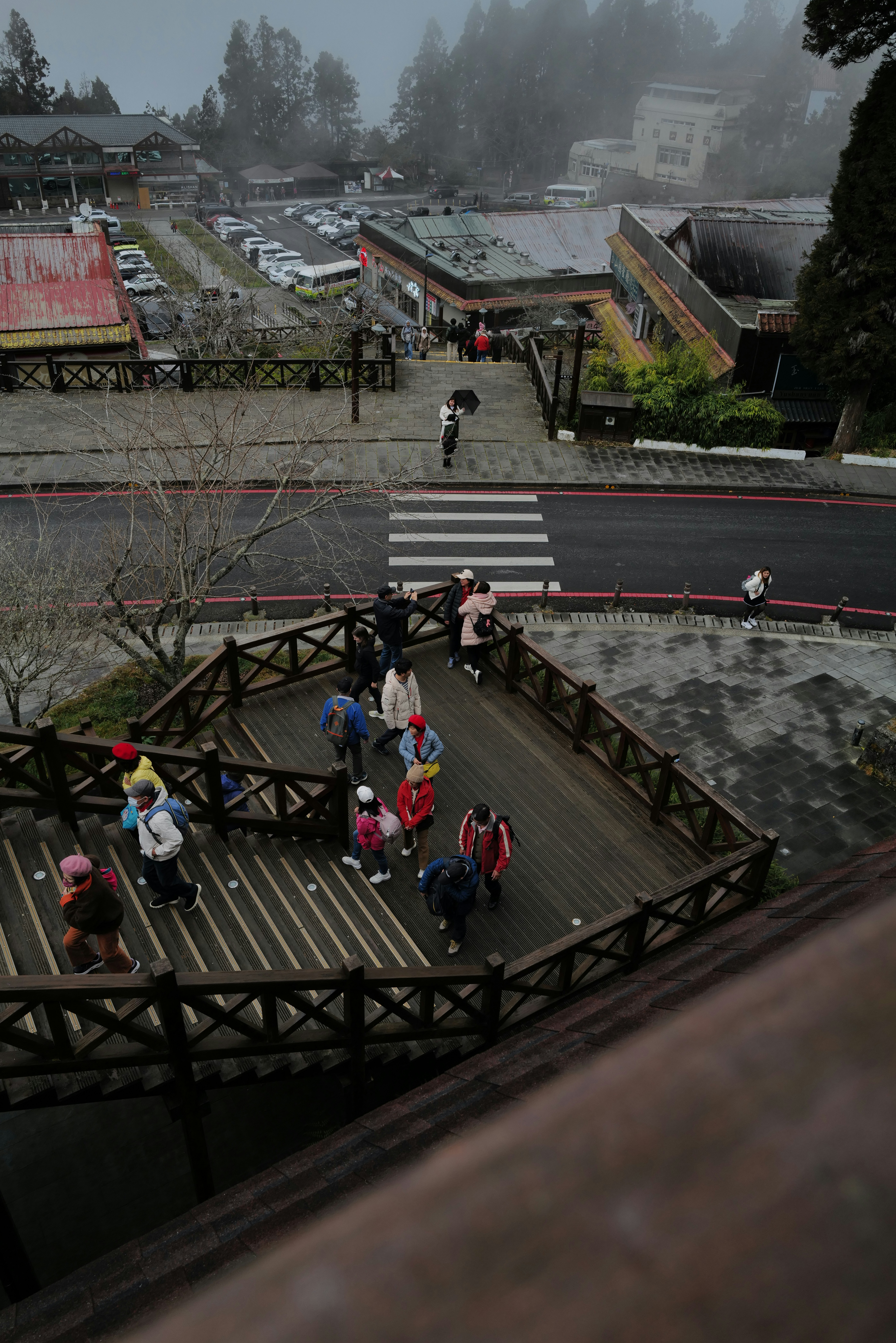 People on a wooden viewing deck overlooking a misty hillside village