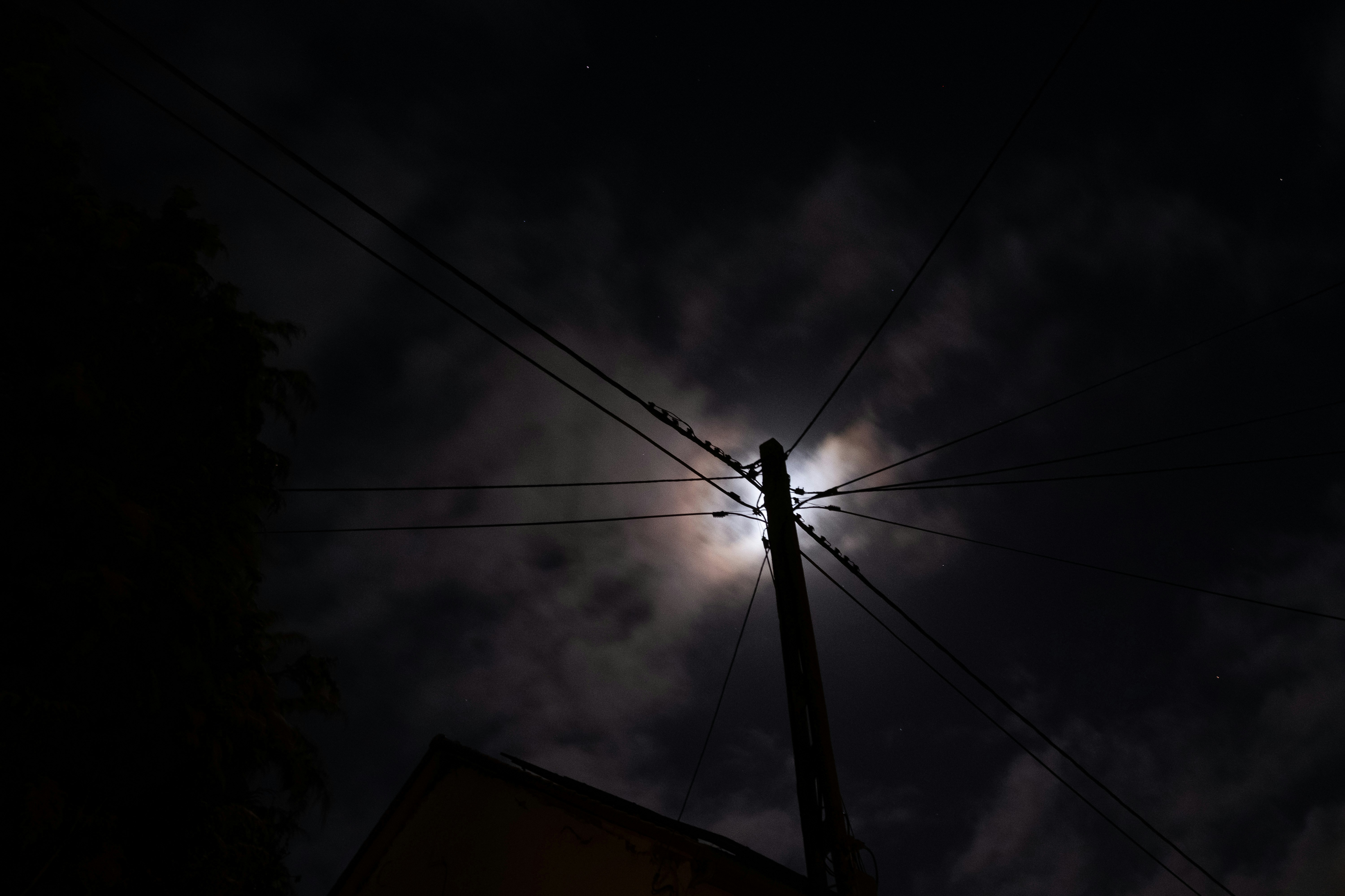Moonlit Utility: Night Sky Weave Around a Power Pole
