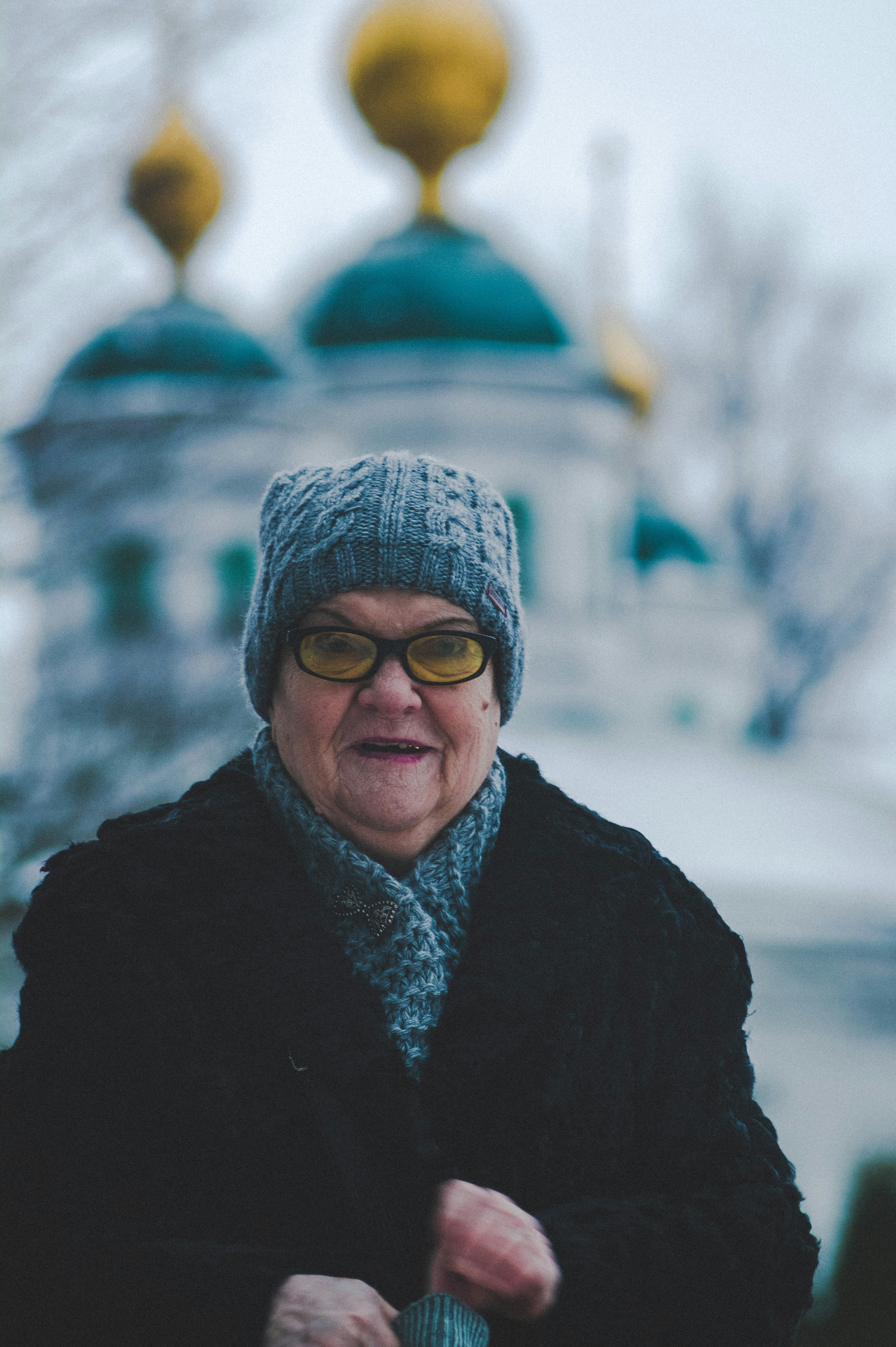 An elderly woman wearing a hat and scarf.