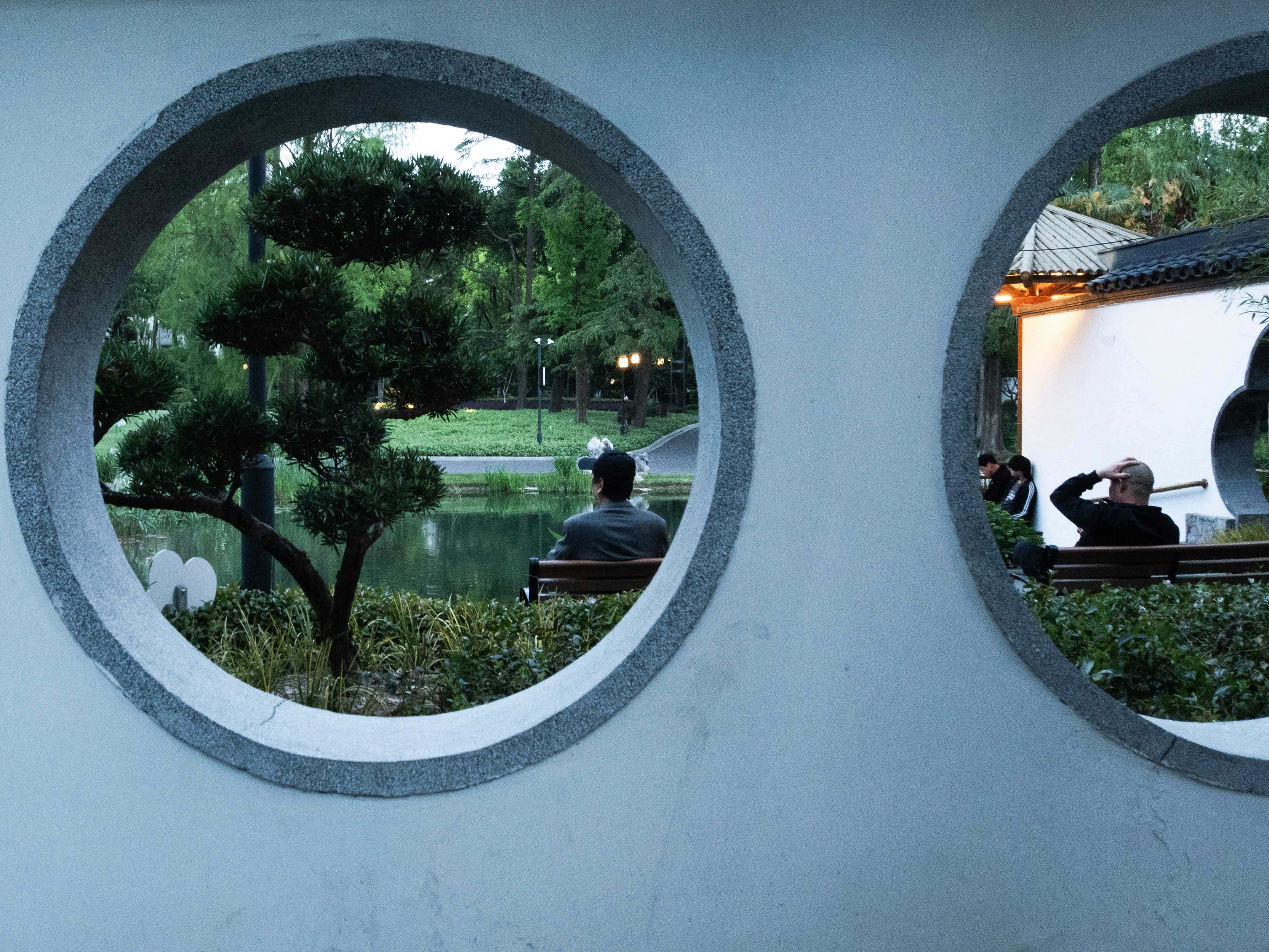 People sitting in a tranquil garden through circular openings.