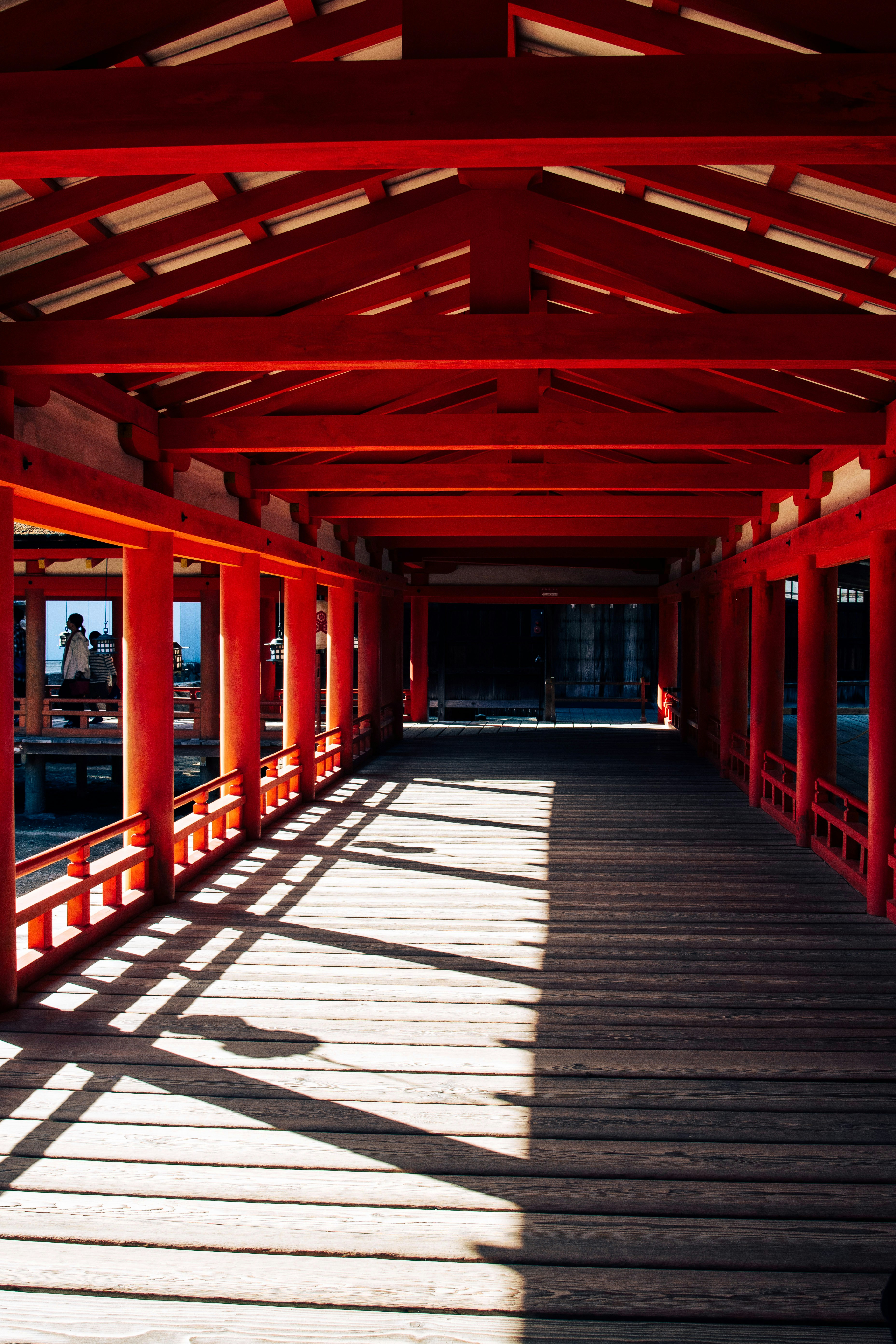 Red Corridor: Shadowed Walkway Under a Canopy of Roof Beams
