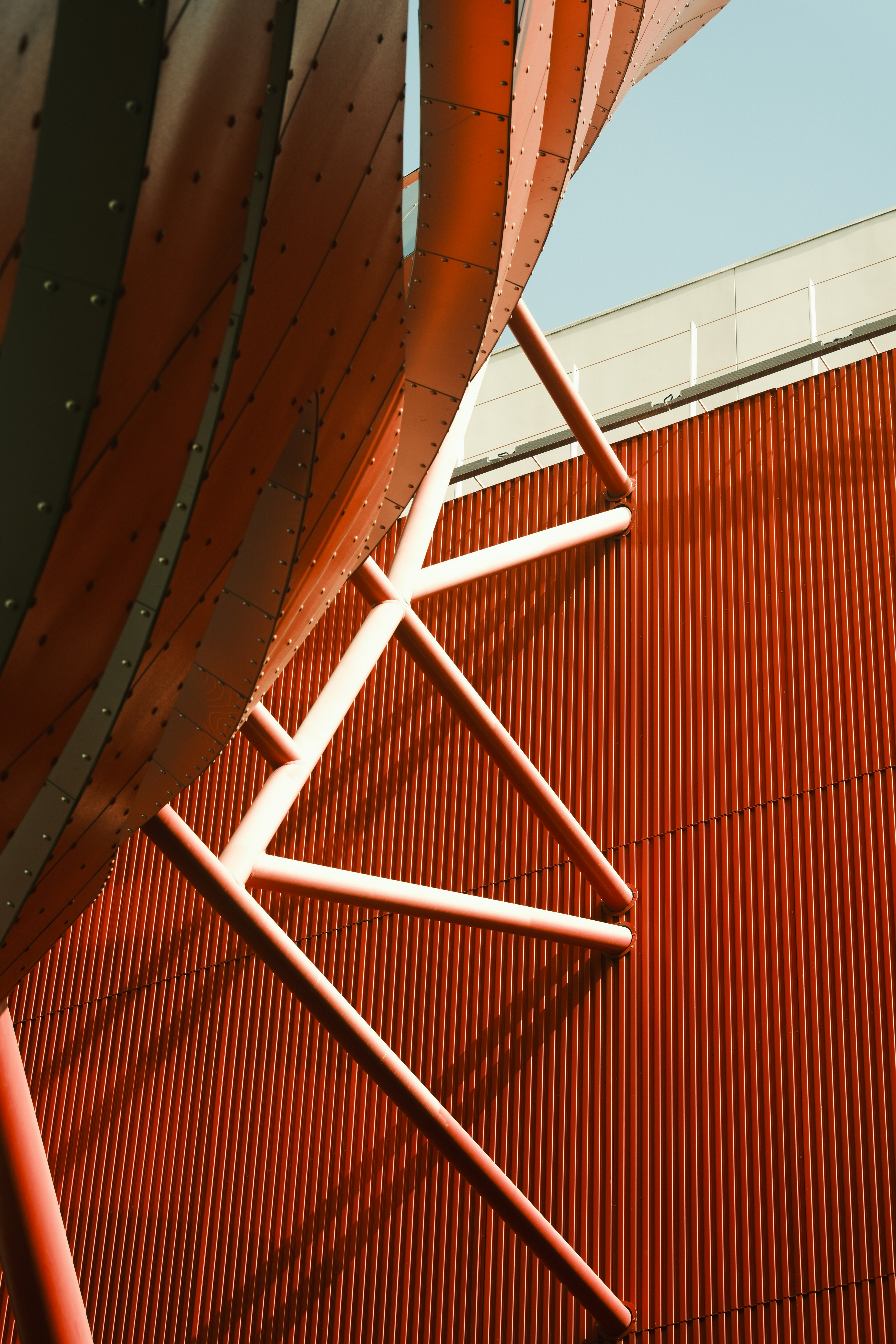 Curved Copper Facade Meet Red Steel: A Play of Architecture and Geometry