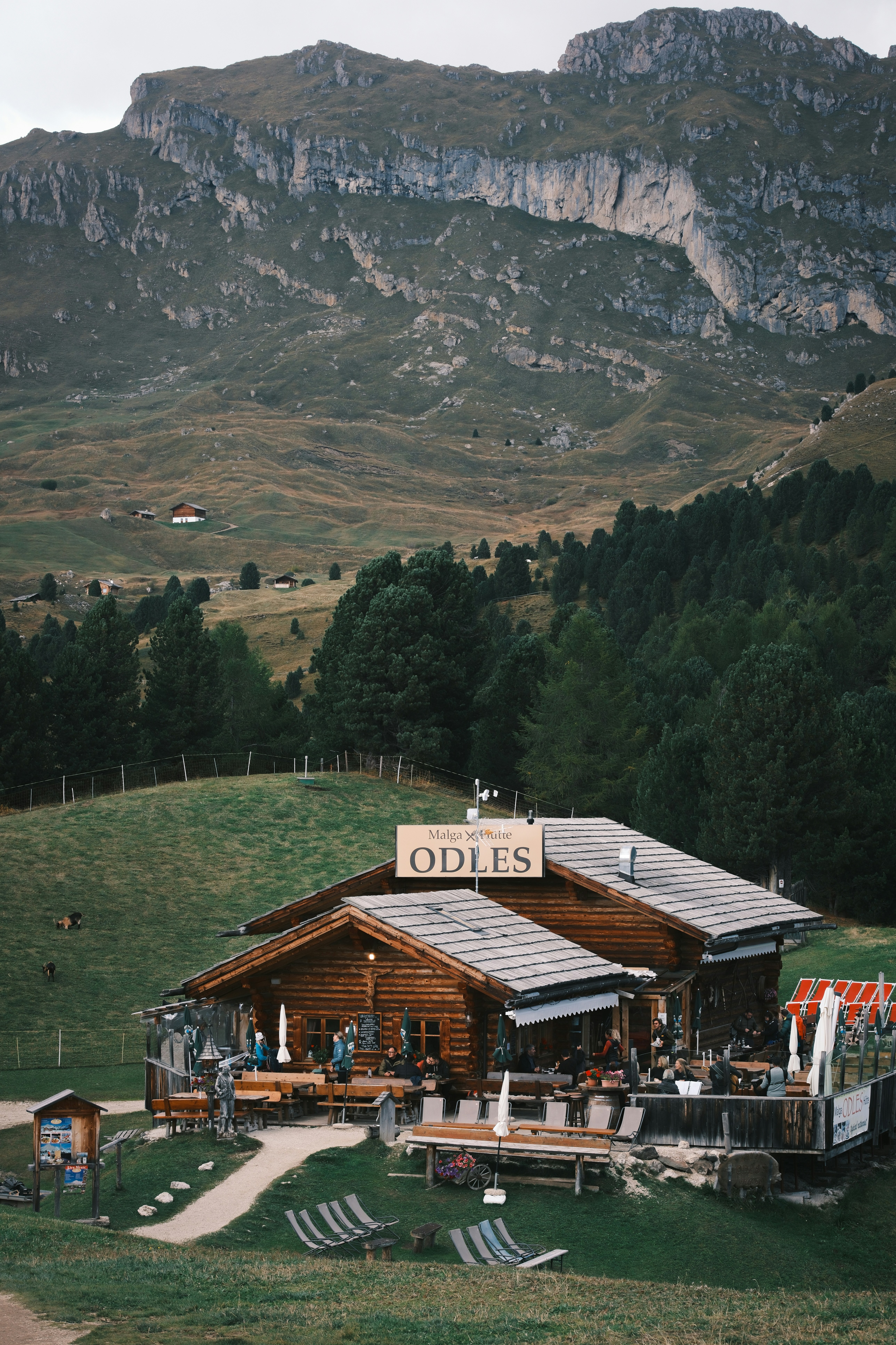 Wooden Alpine Café Nestled at the Foot of a Rocky Crest