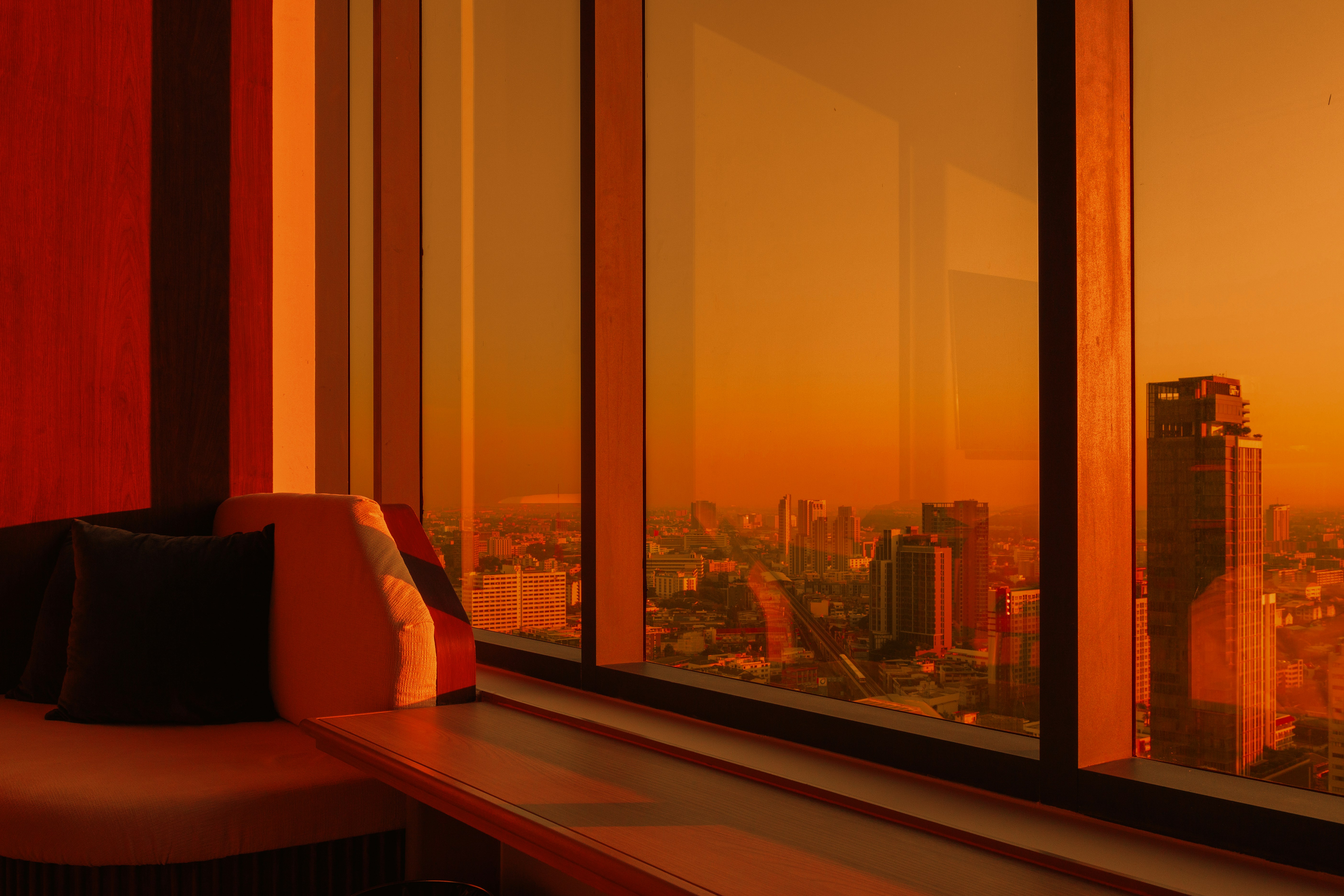 Sunset Lounge: Warm Tones Cascading Over a Cityscape from a Plush Corner