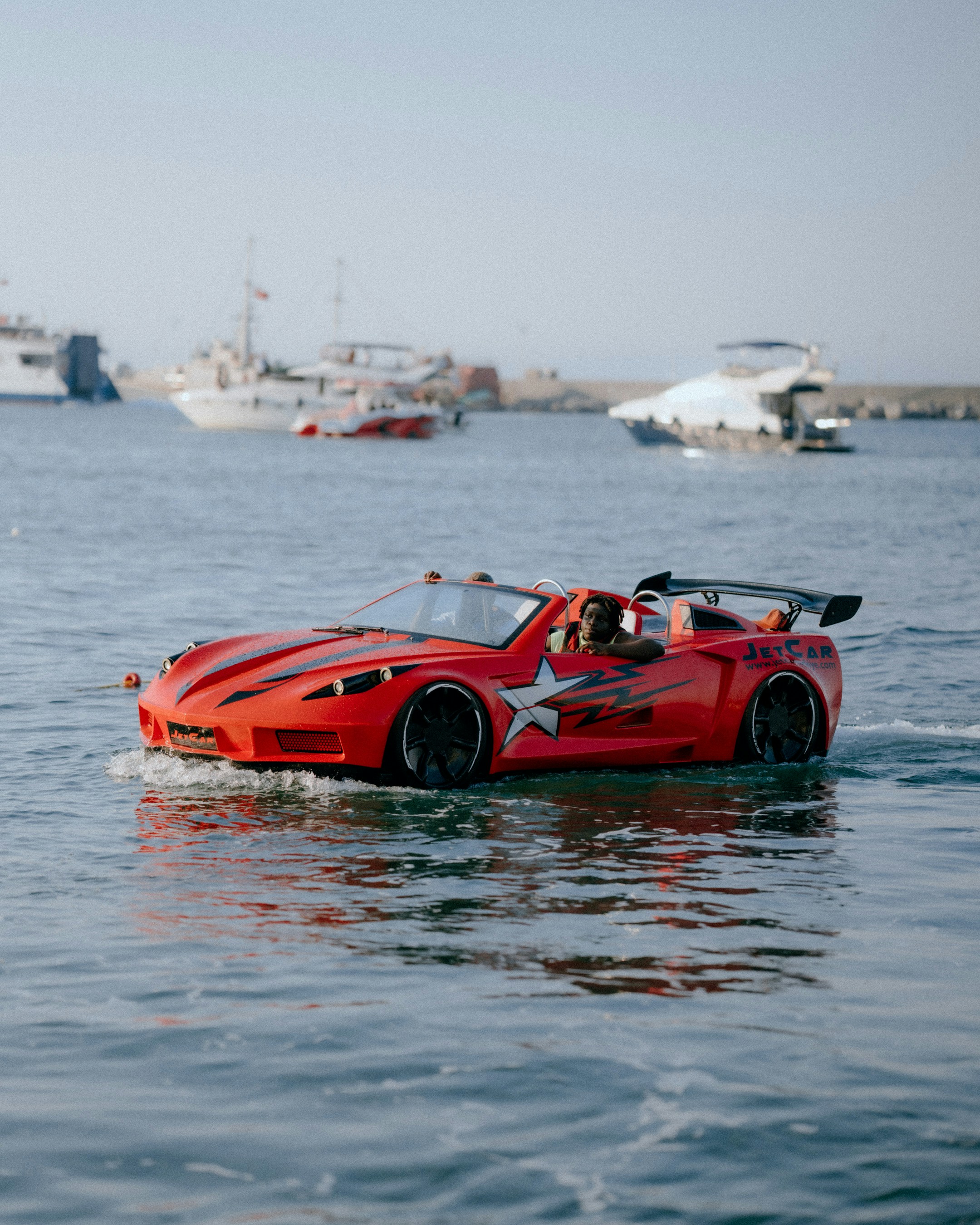 Red Thunder on the Wake: A Convertible Speedster Passes Portside