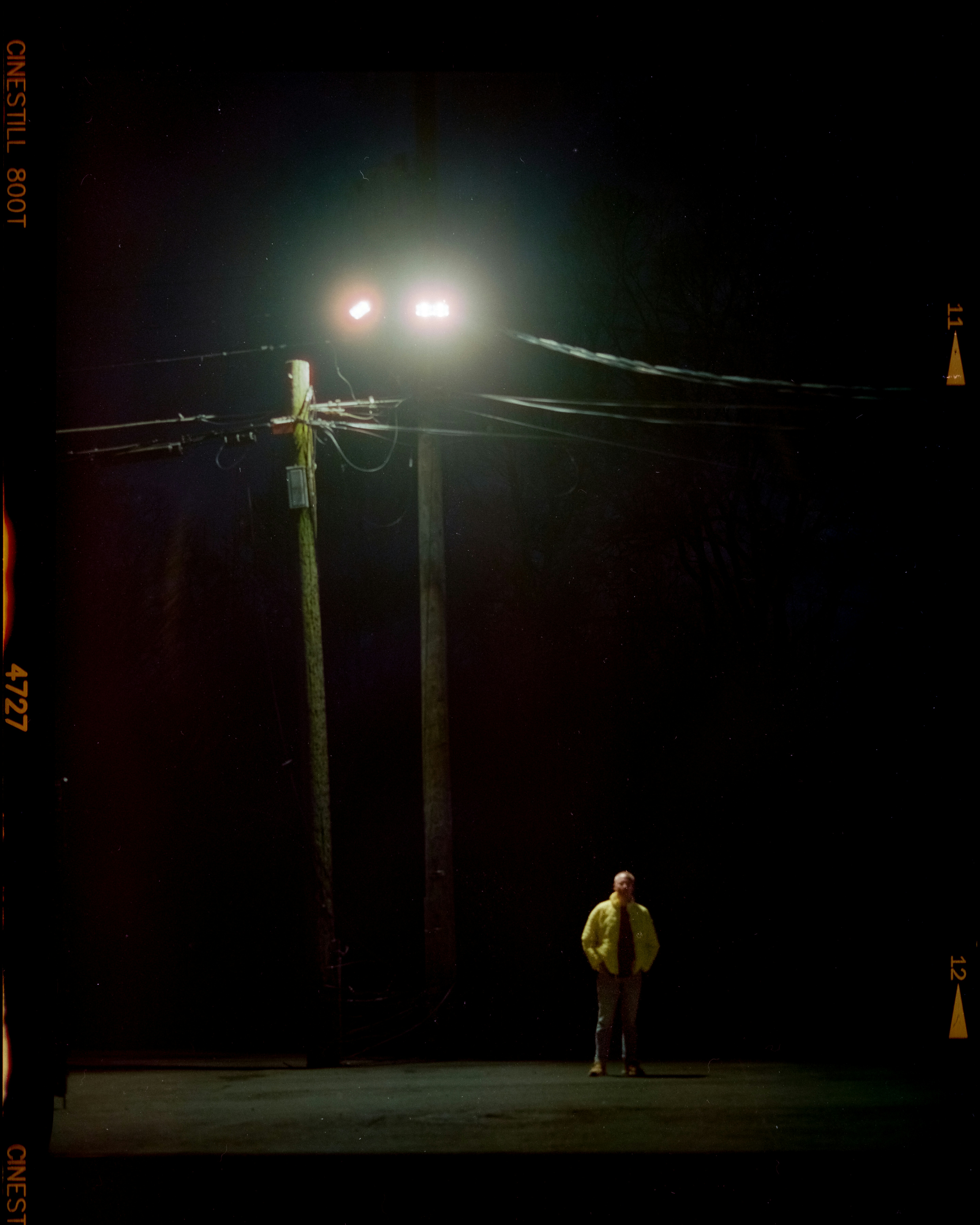 Night Silence Under the Lamp: Lone Figure Beneath Electric Poles