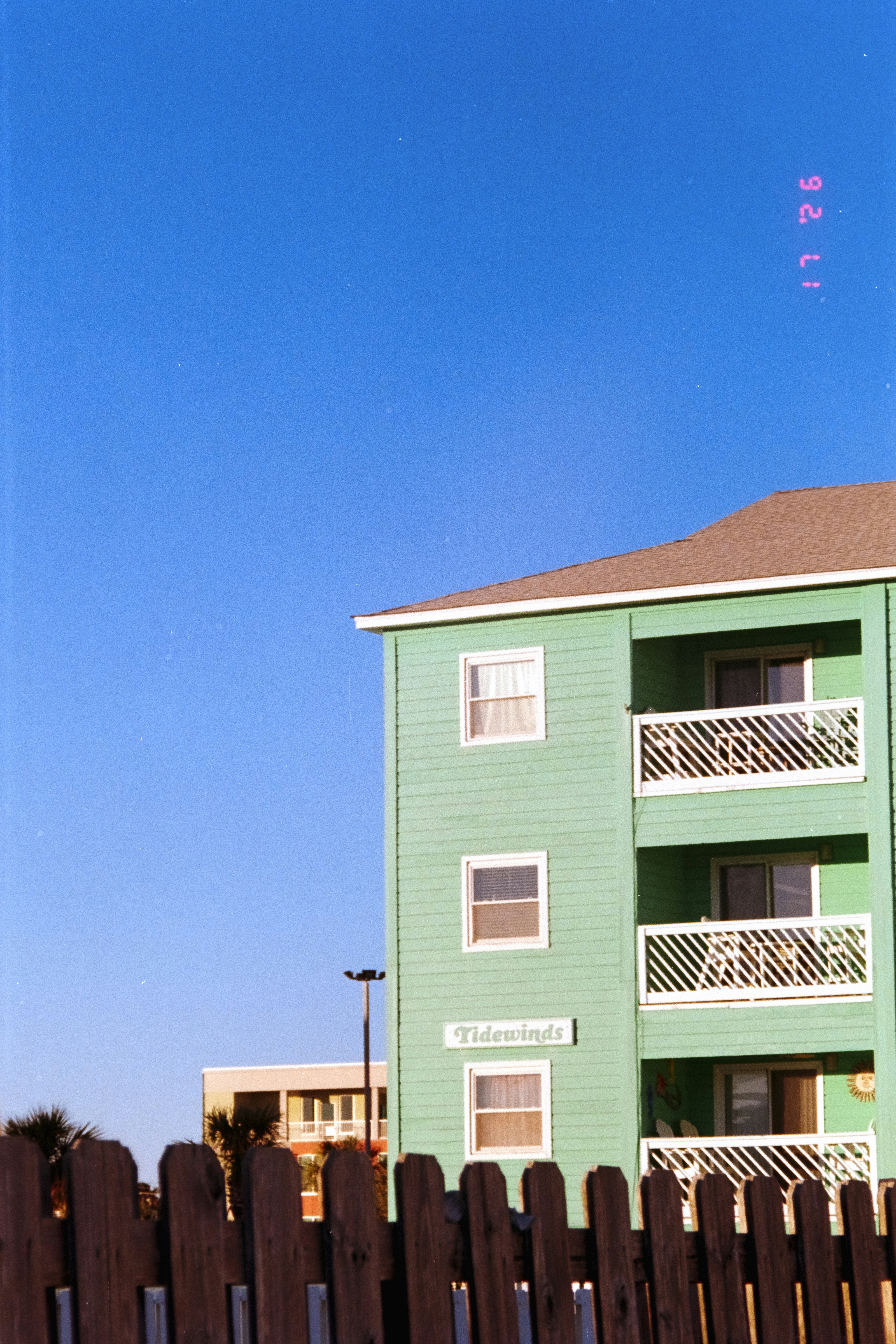 Green Condo with White Railings Under a Clear Blue Sky