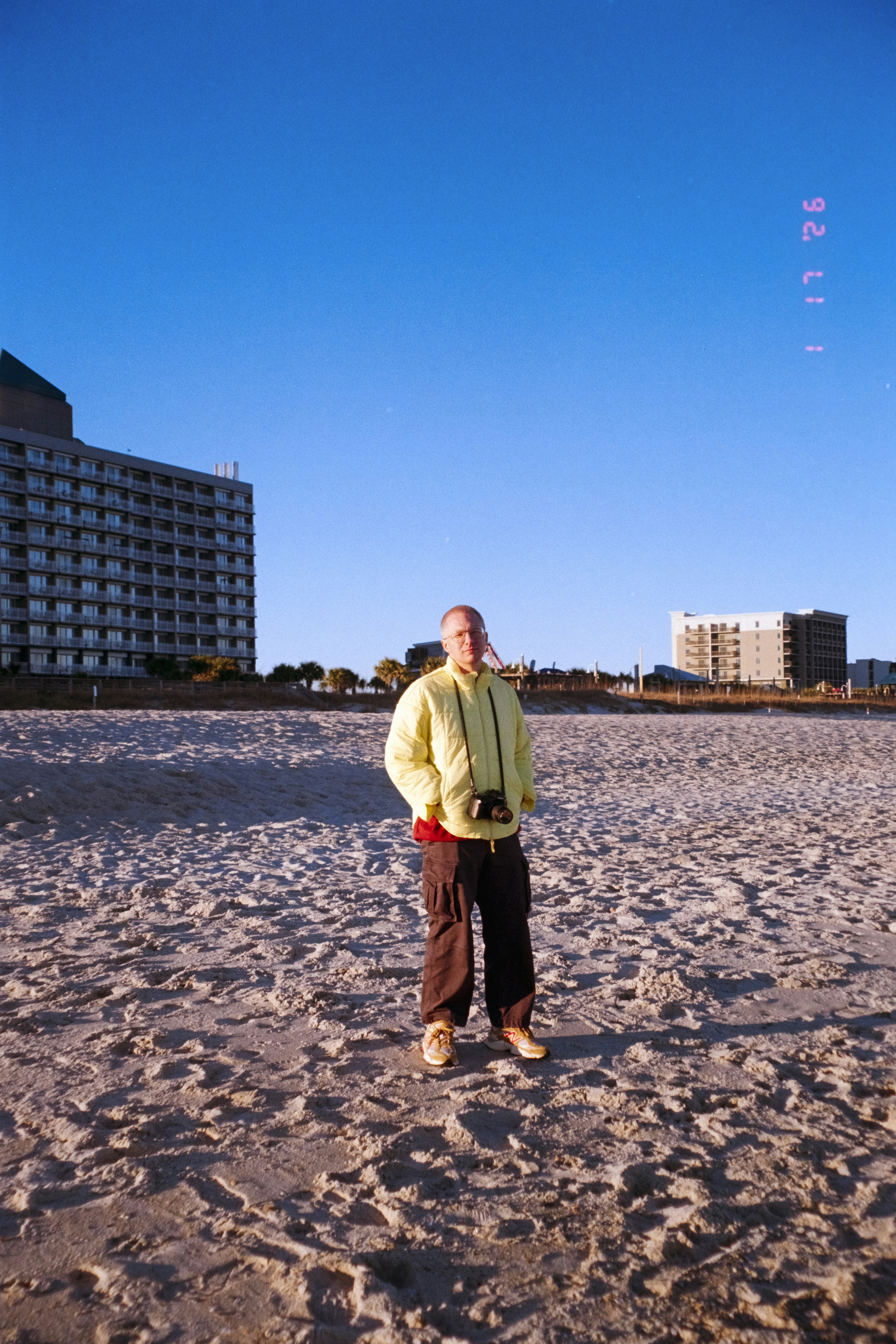 Man in Neon Jacket Stands Quietly on Sunny Beachfront