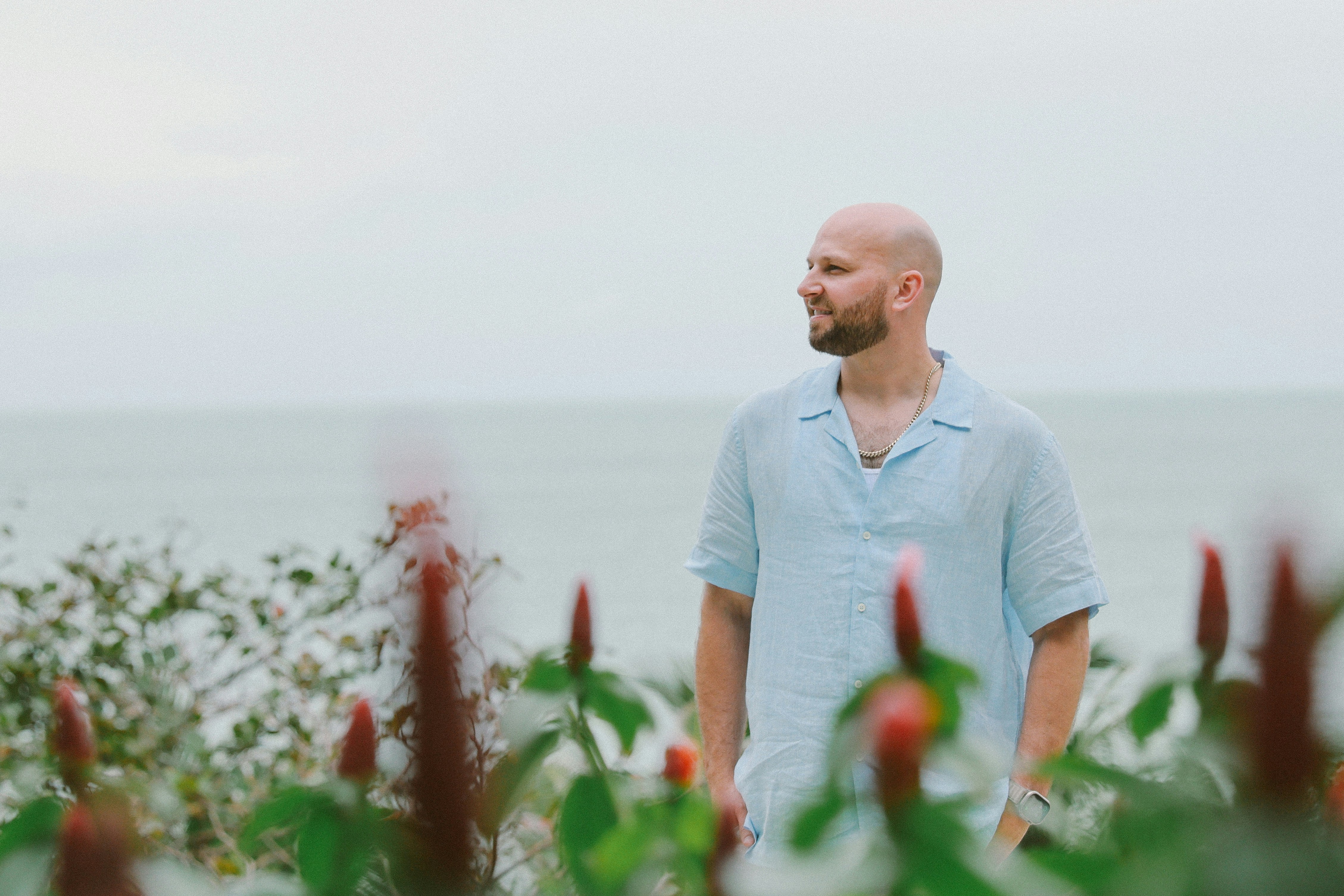 Coastal calm: a man in light-blue linen stands among sea-sprout greens