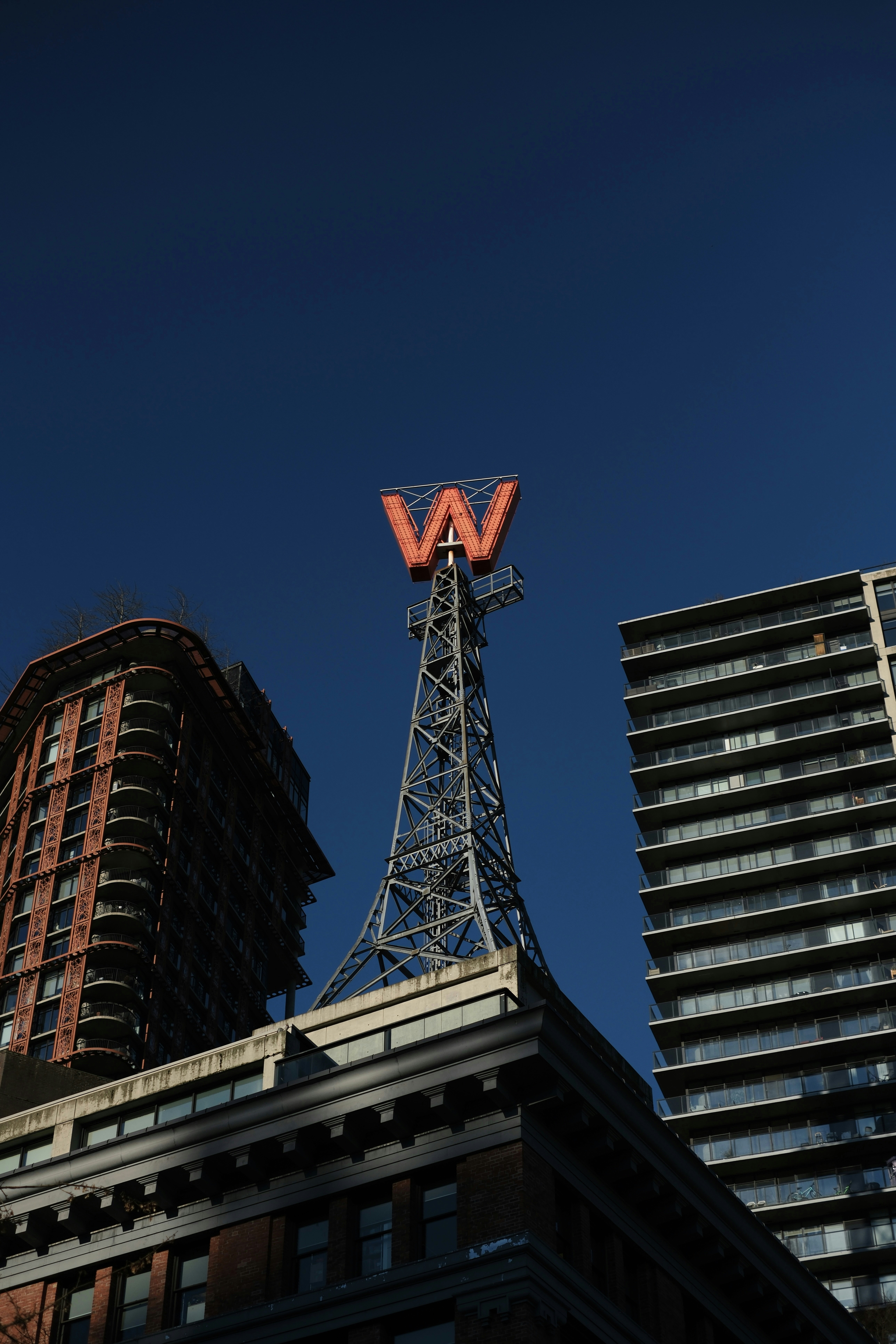 The W Above the City: A Neon Emblem Over Urban Facades