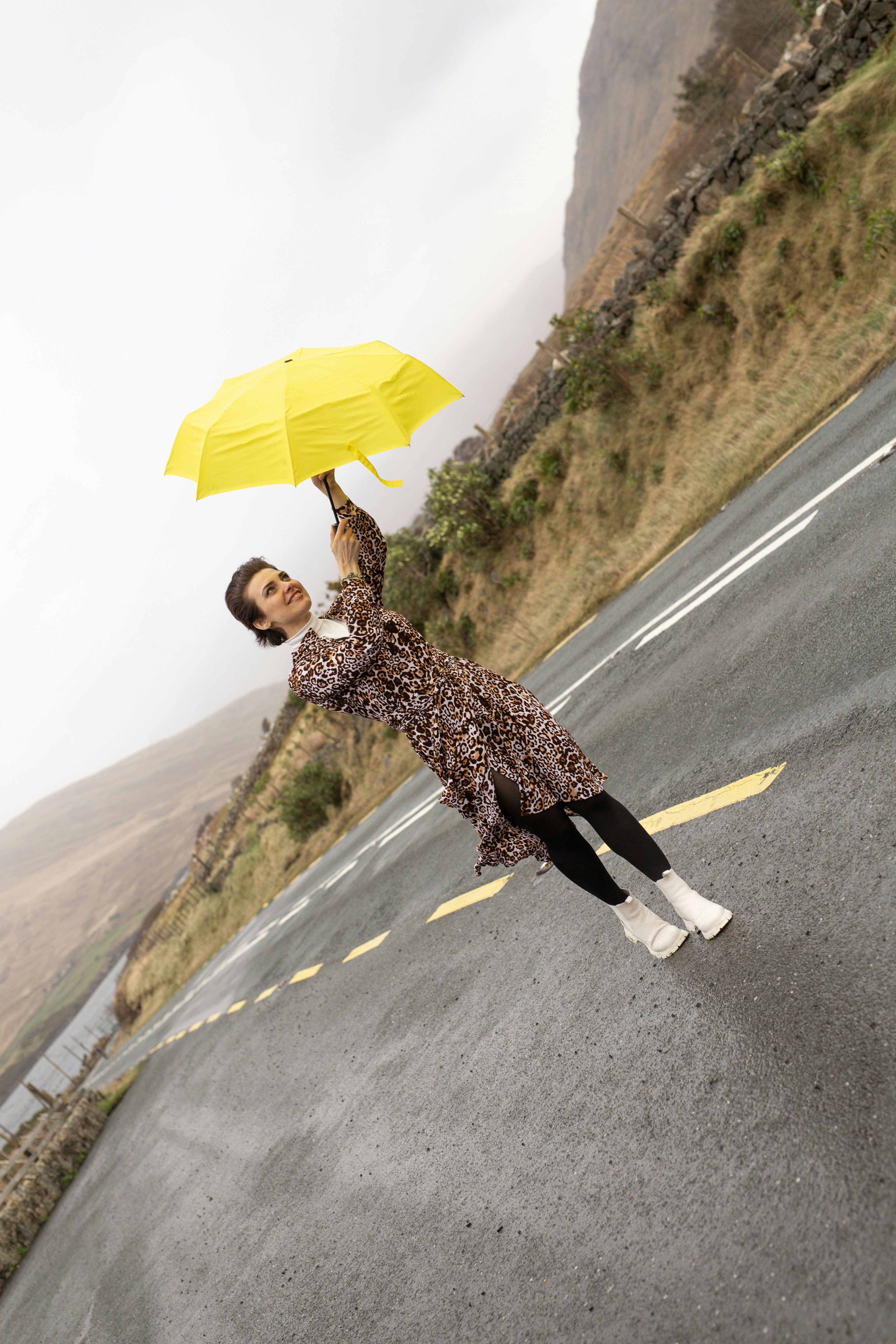 Yellow Umbrella Arc: A Portrait Against a Mountain Road