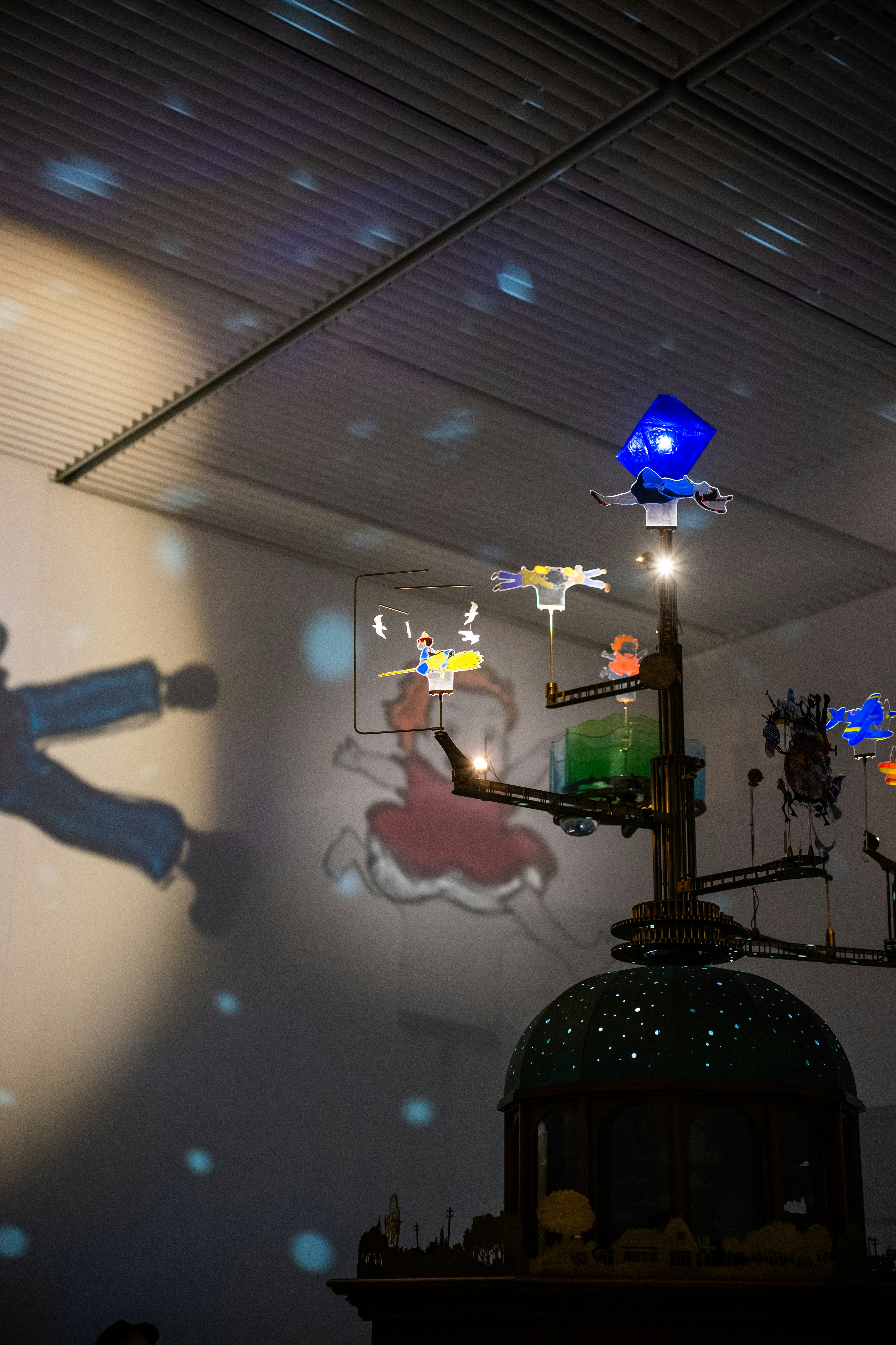 Ornate celestial machine crowned by a blue beacon in a shadowy gallery