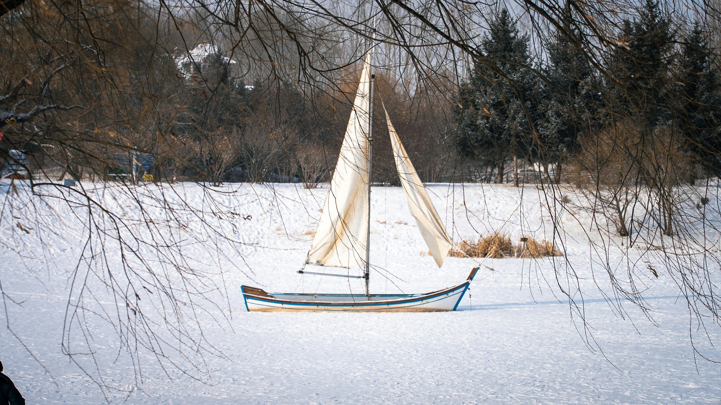 A sailboat rests on a frozen, snow-covered lake. photo – Free Winter ...