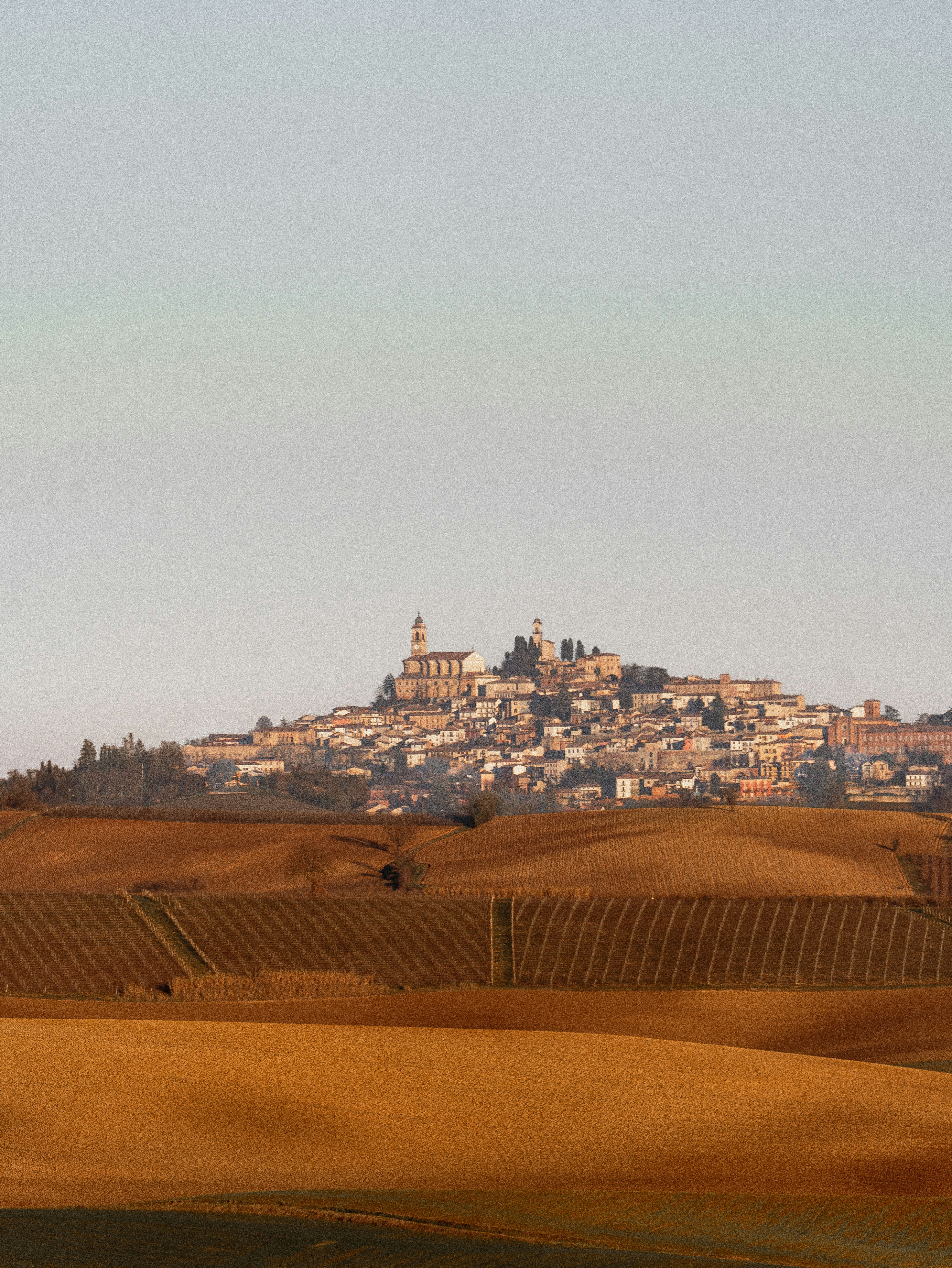 Hilltop Village Rising from Golden Fields at Dusk