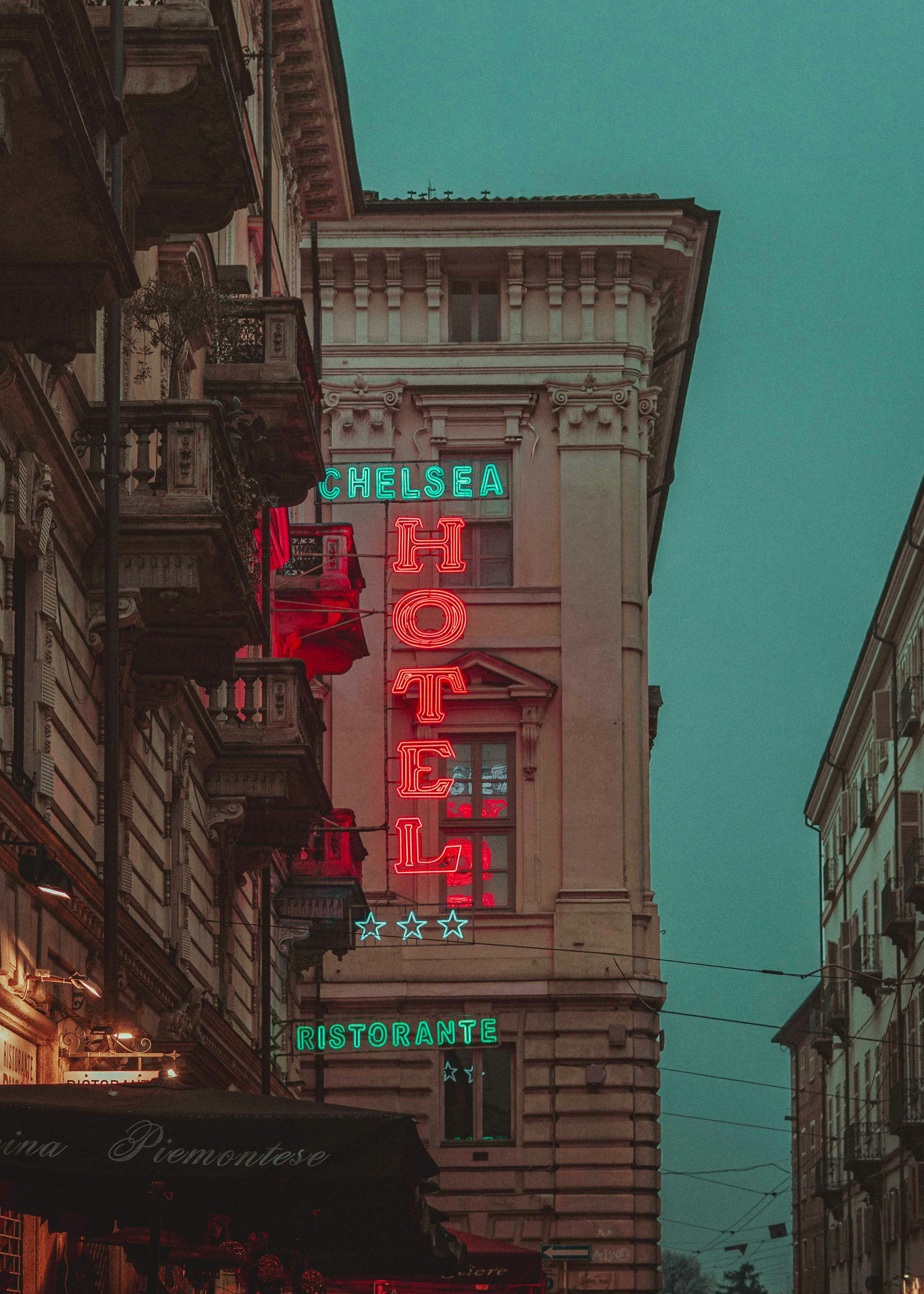 Neon vertical HOTEL sign lighting up a European street at dusk