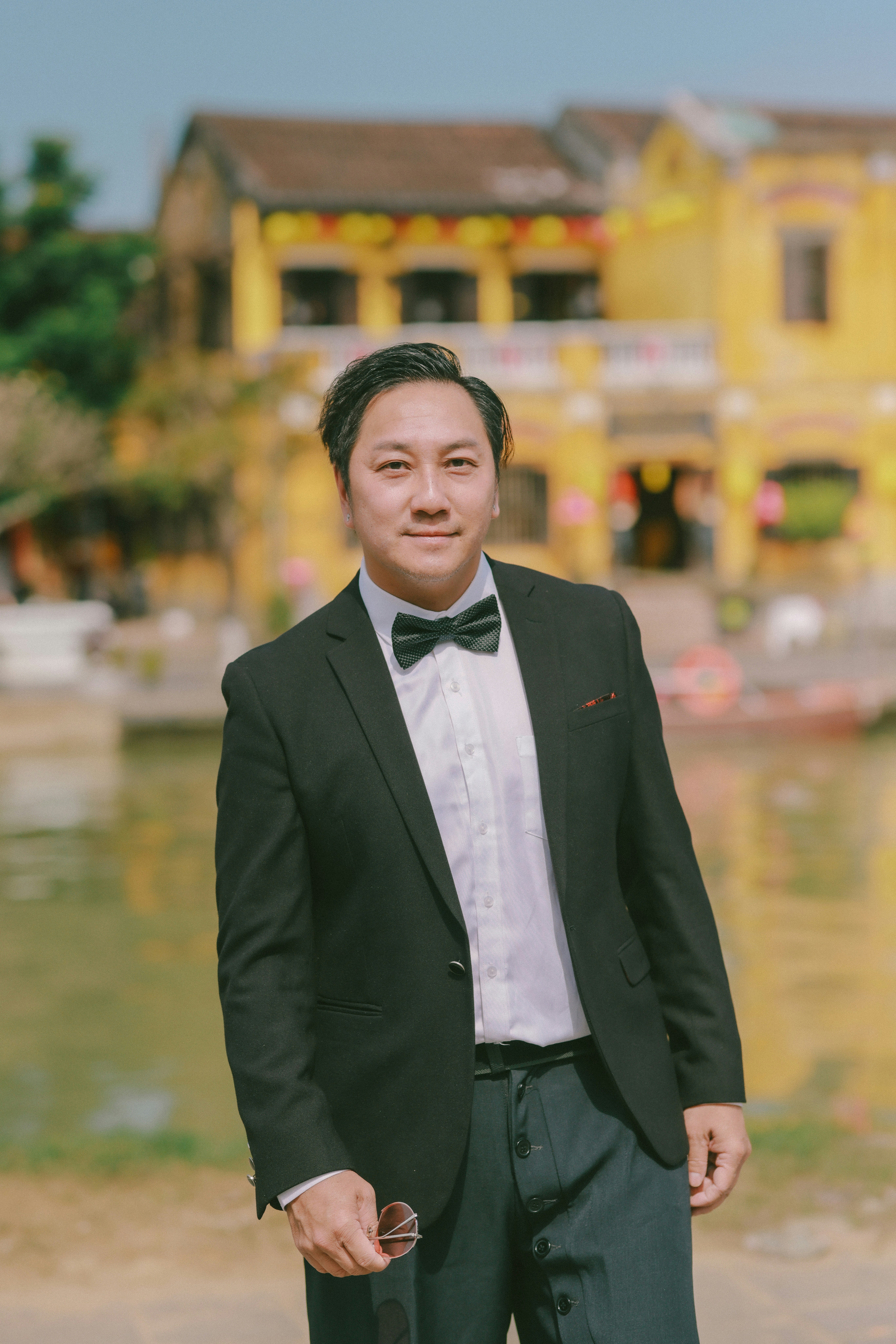 Gentleman in Black Tie by a Sunlit Village Fountain