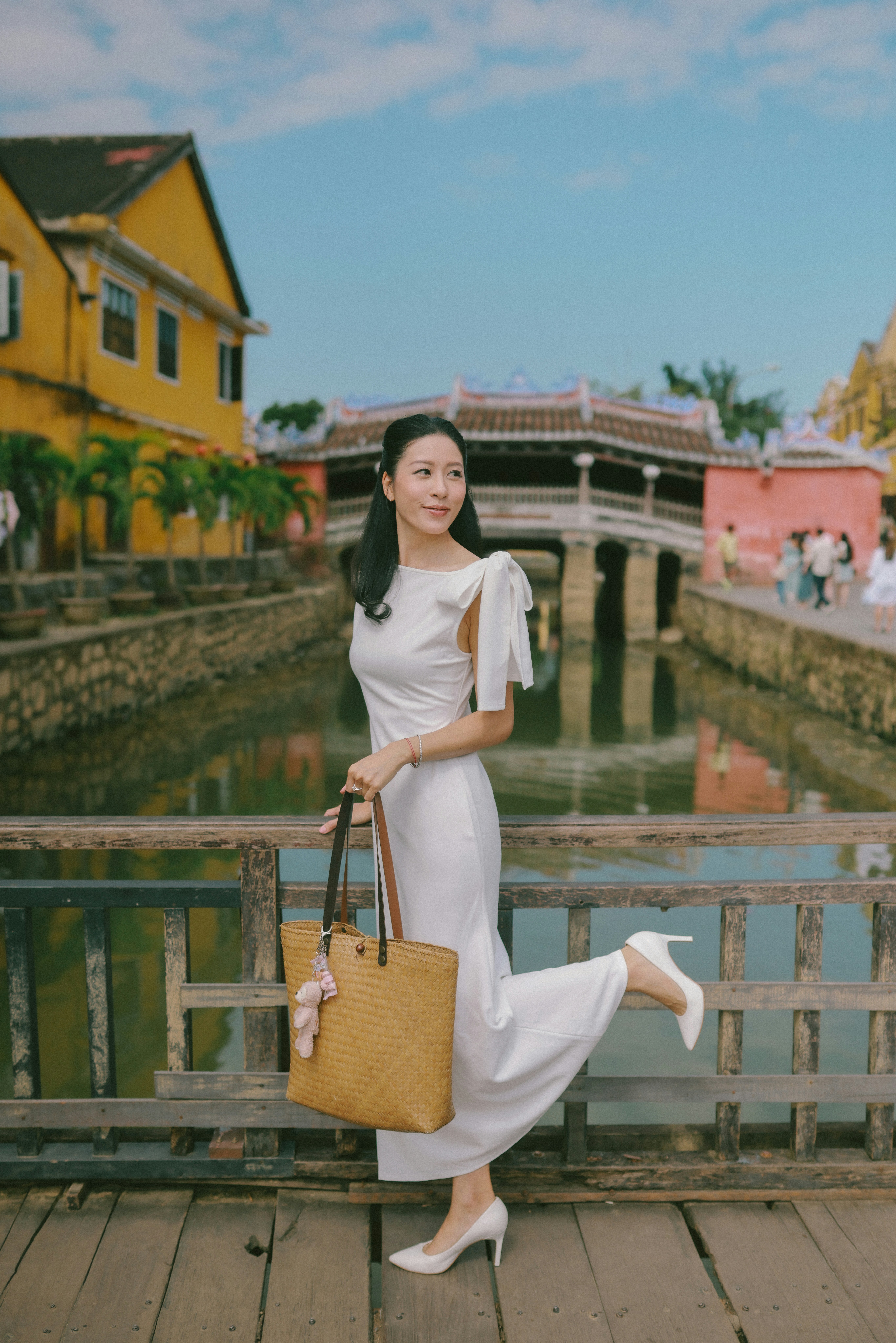 White-dress stroll on a sunlit canal bridge