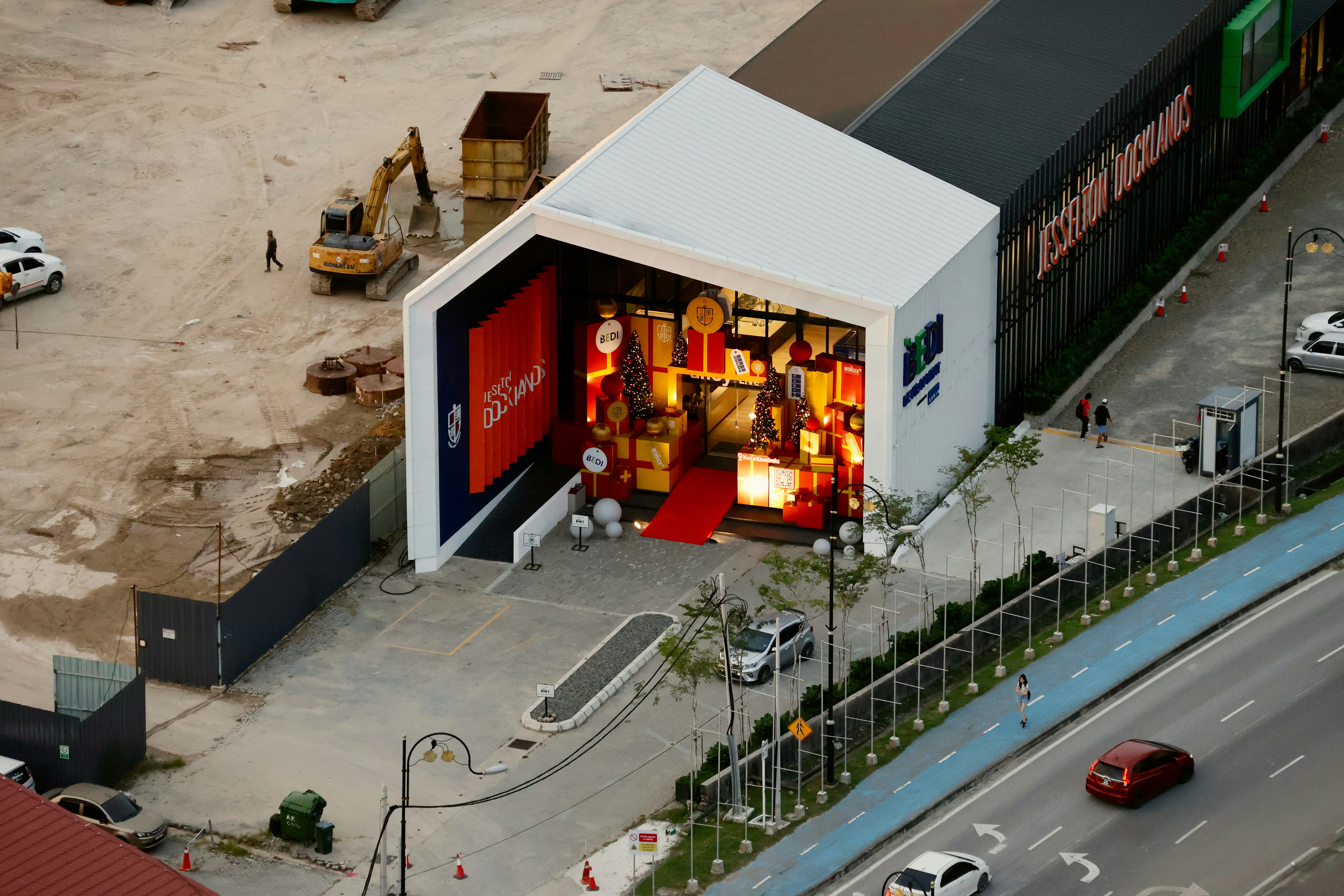 Glow inside a temporary showroom: illuminated pavilion on a construction site beside a highway
